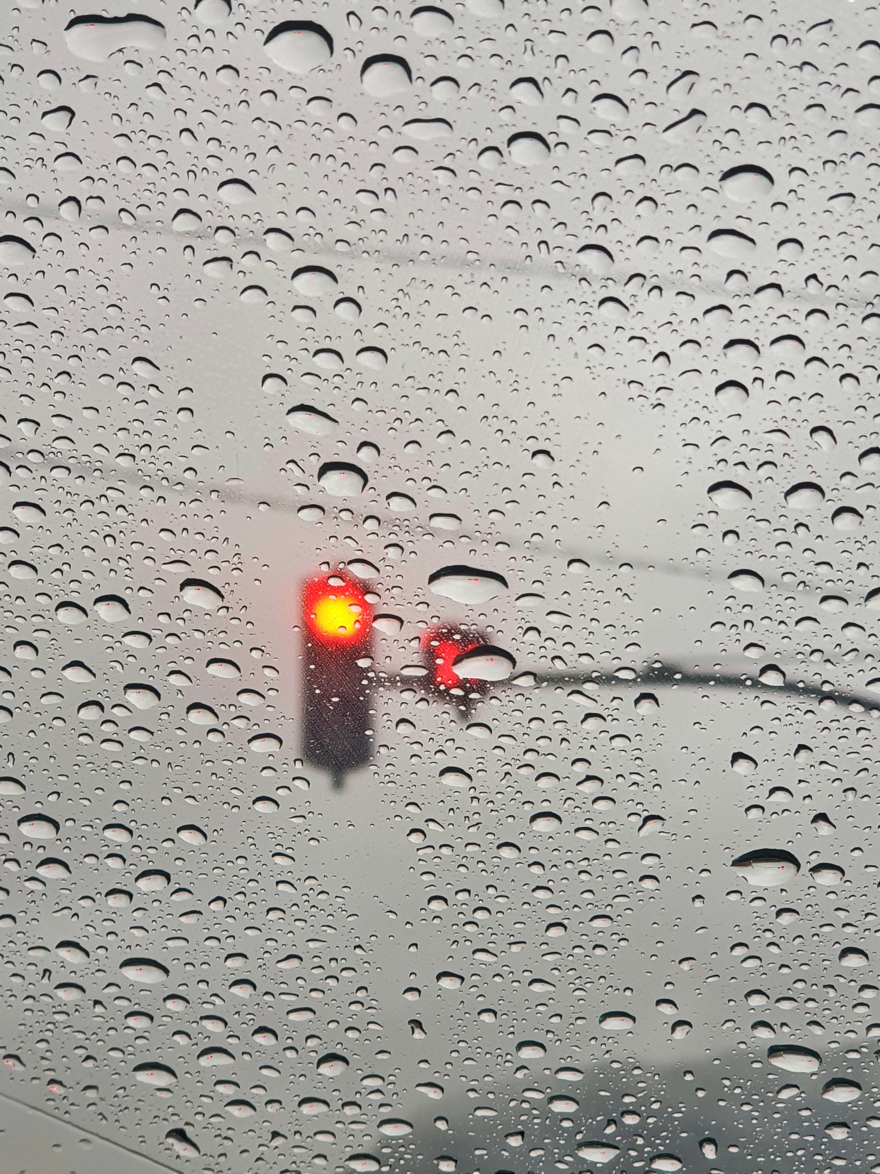 a traffic light sitting on top of a rain covered windshield