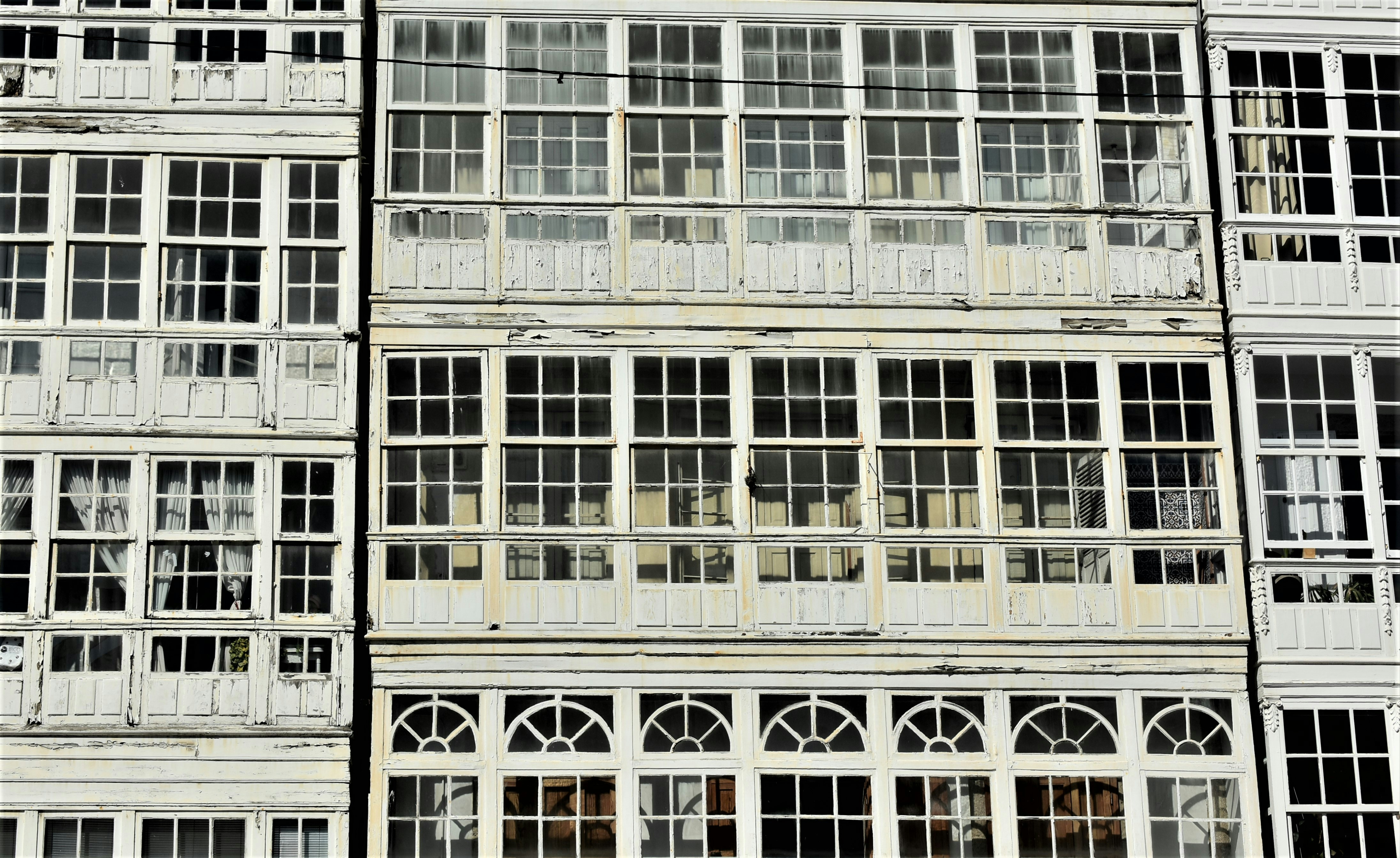 Facade of a large building with numerous white-framed windows and a clock.