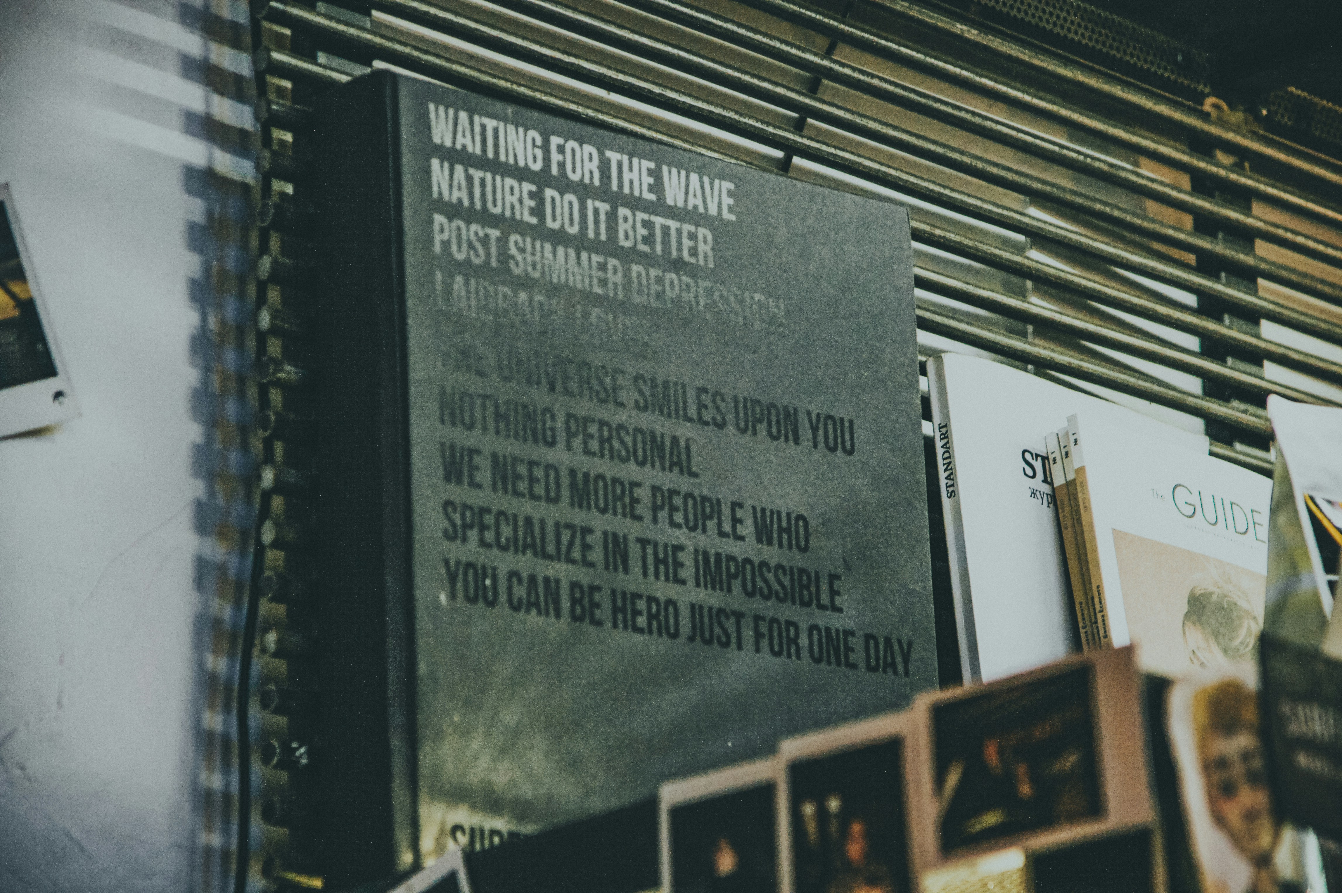 Blurred text on a signboard in a dimly lit interior, with photos and books nearby.