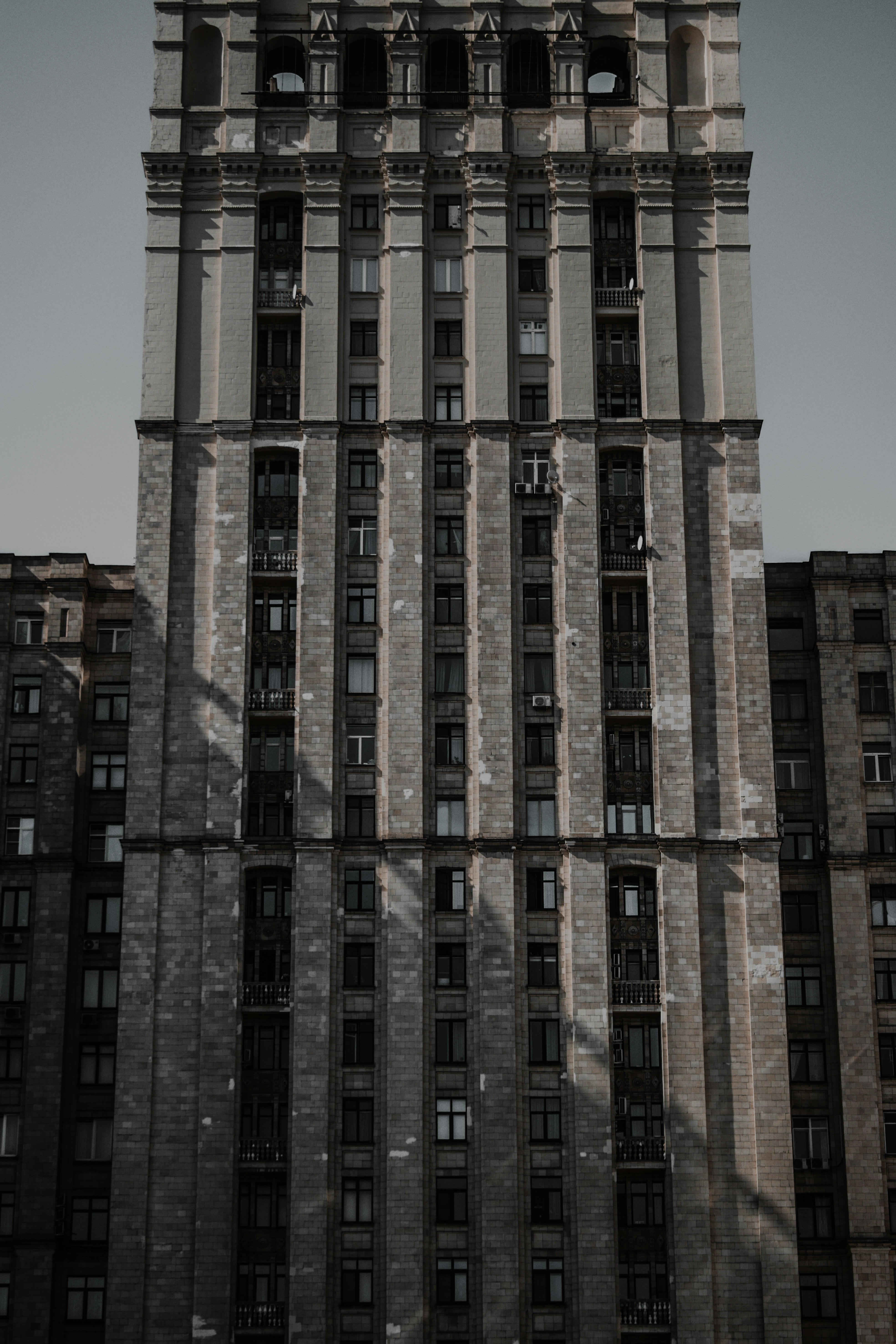 Vertical view of a weathered residential building showcasing intricate window patterns and shadows.