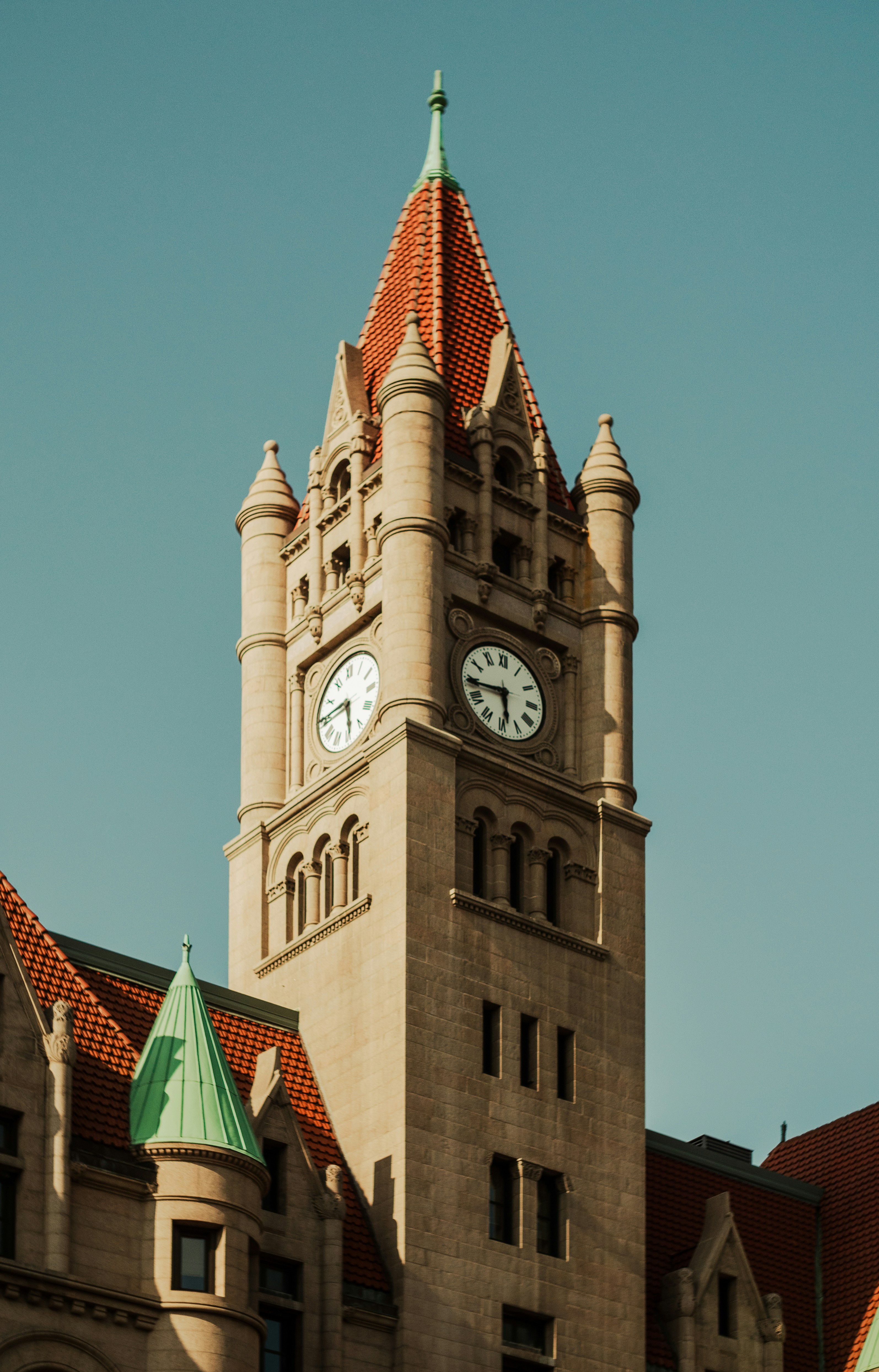 A historic clock tower featuring ornate architecture and a vibrant red roof, set against a clear blue sky.