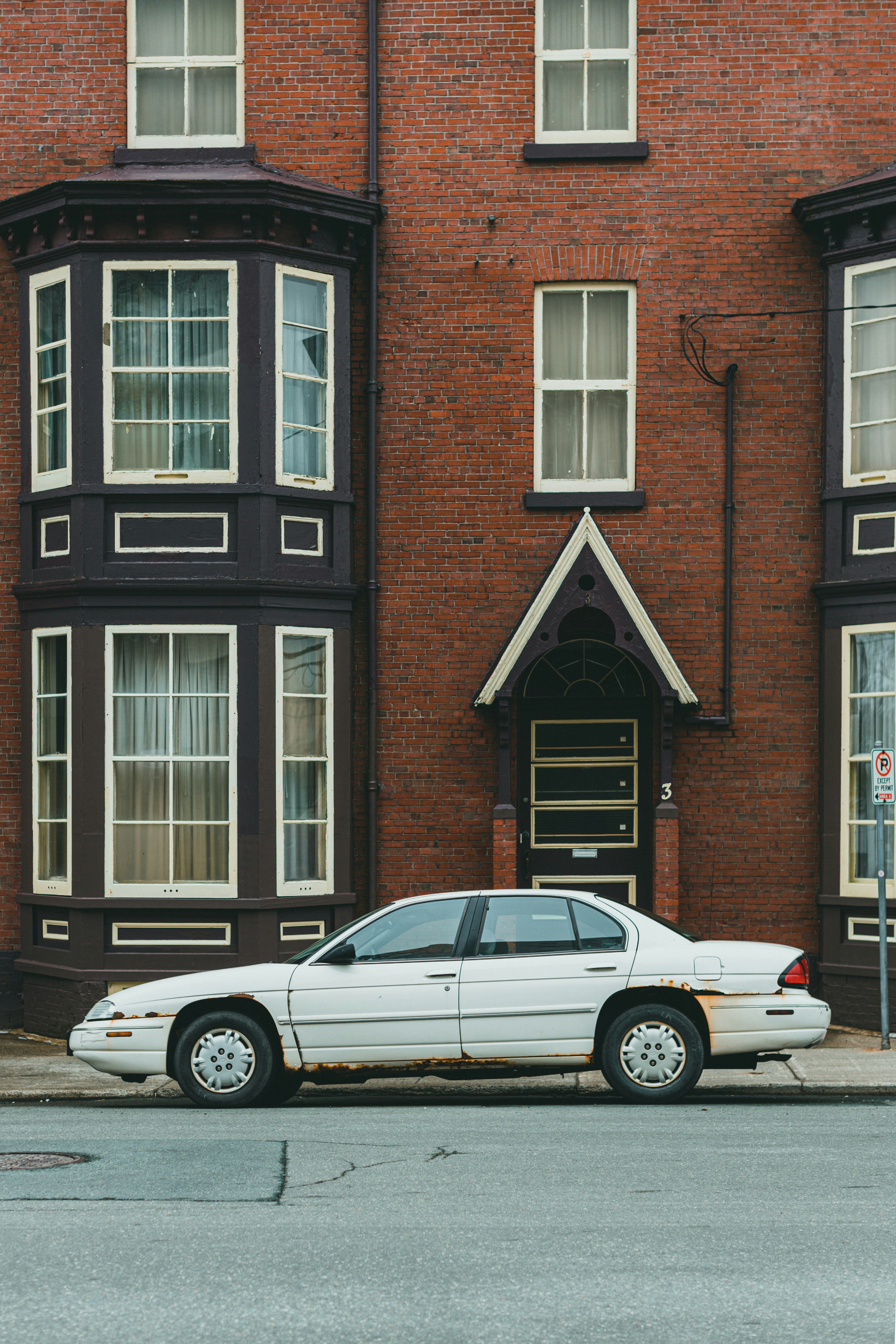 White Sedan at the Entrance: a brick townhouse street portrait