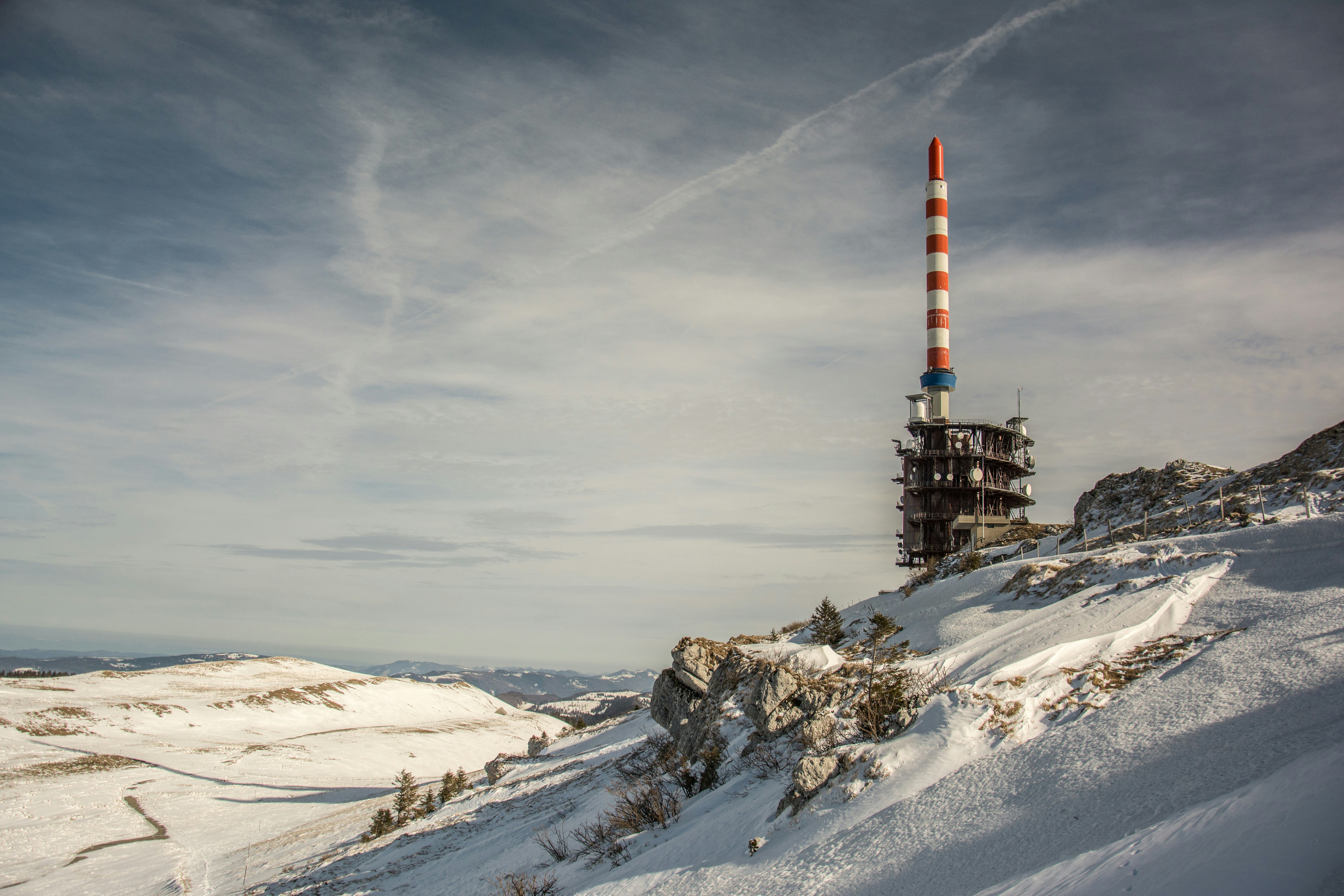 A red and white tower sitting on top of a snow covered mountain photo ...