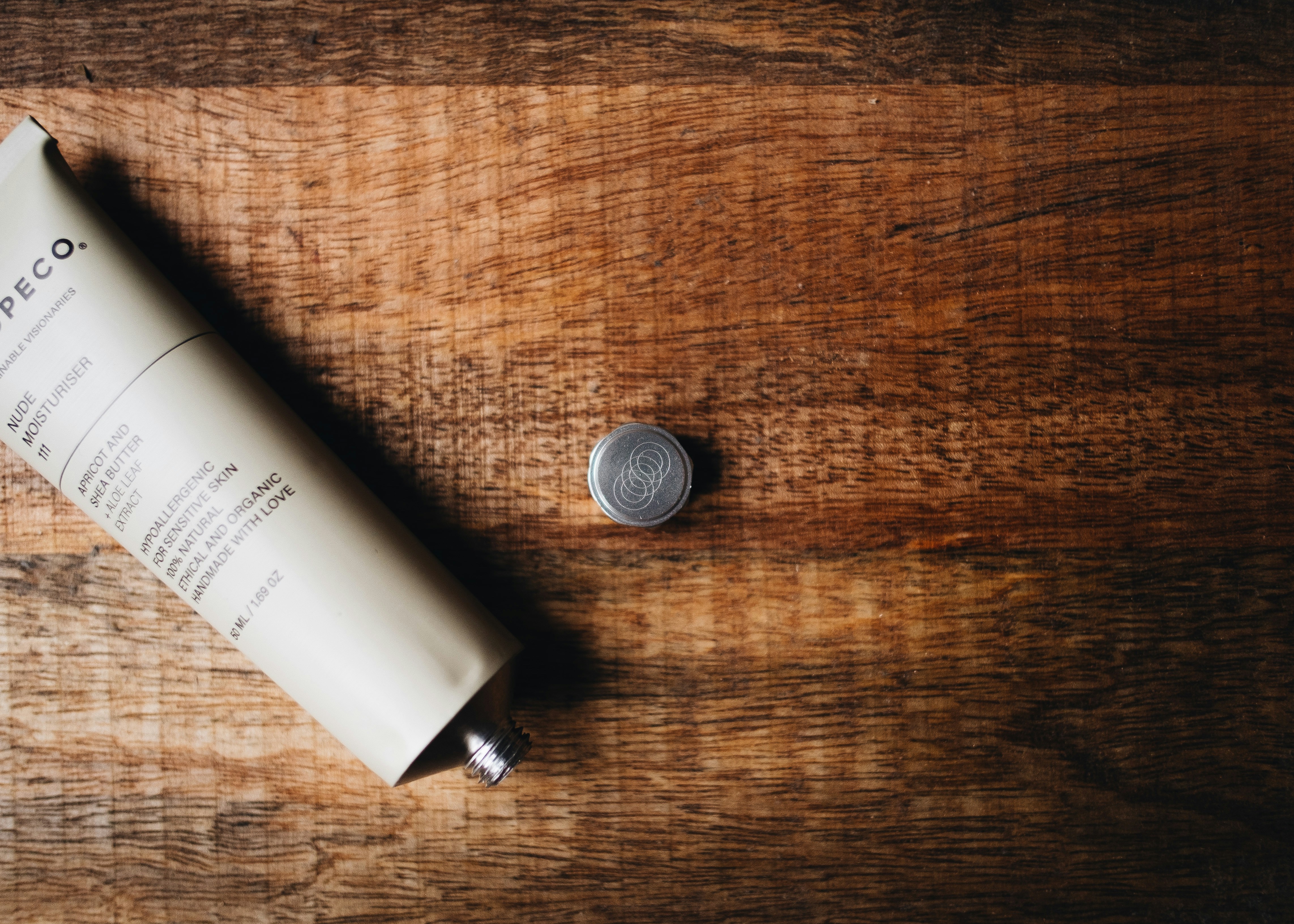A tube of sunscreen next to a tube of sunscreen on a wooden surface ...