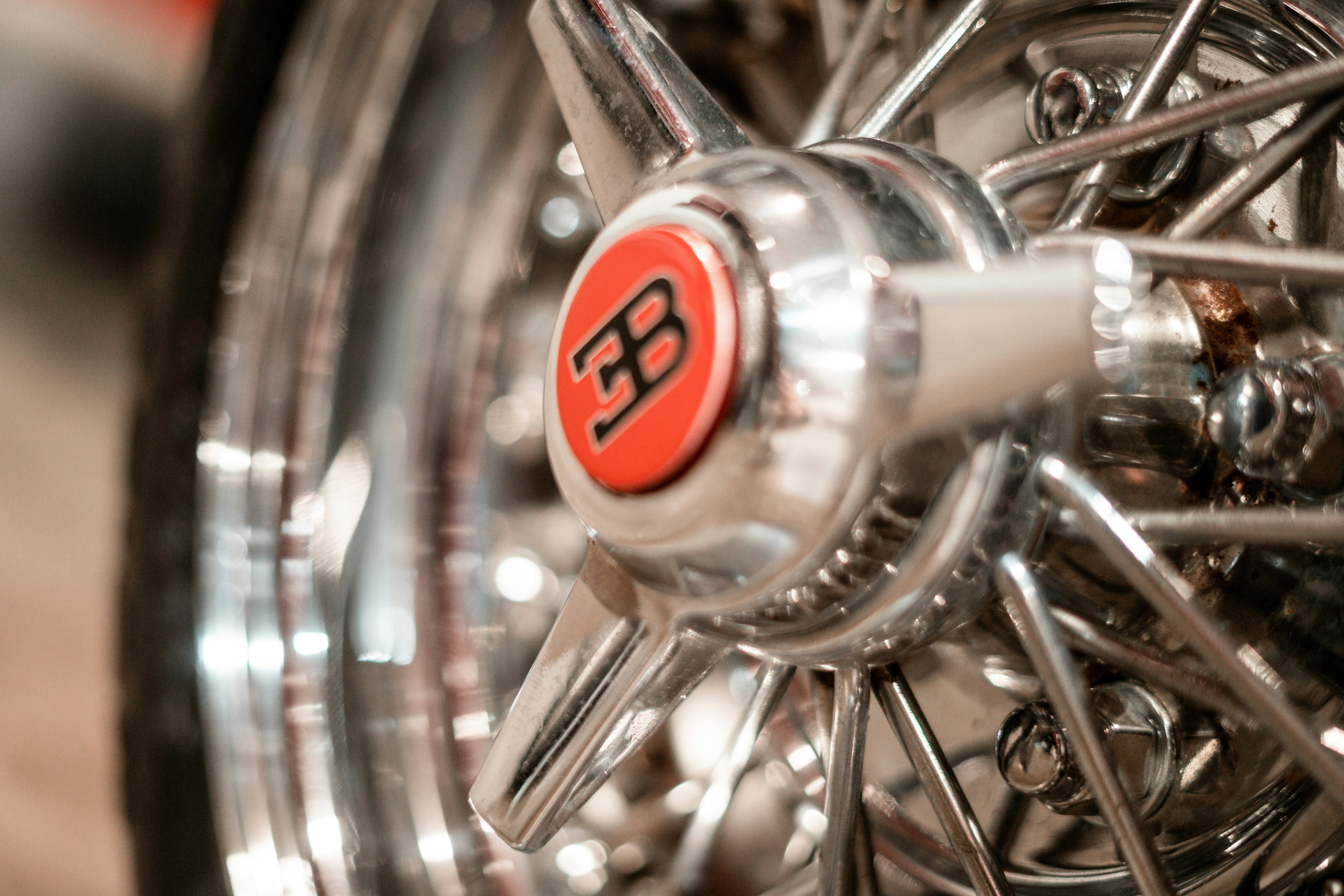 Chrome Hub with Red BB Badge: A Close-Up of Vintage Spoked Wheel Detail