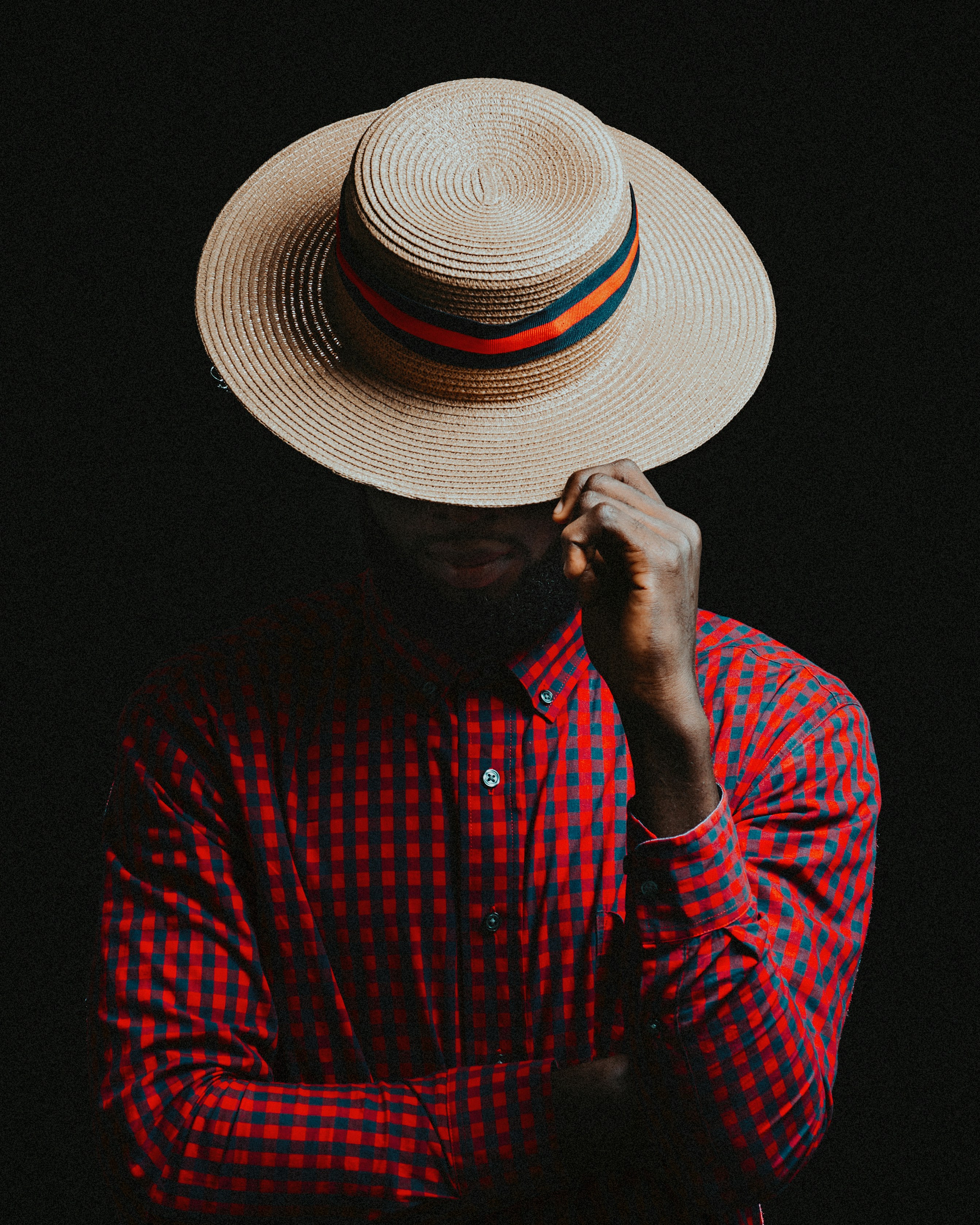 a man wearing a red and black checkered shirt and a straw hat