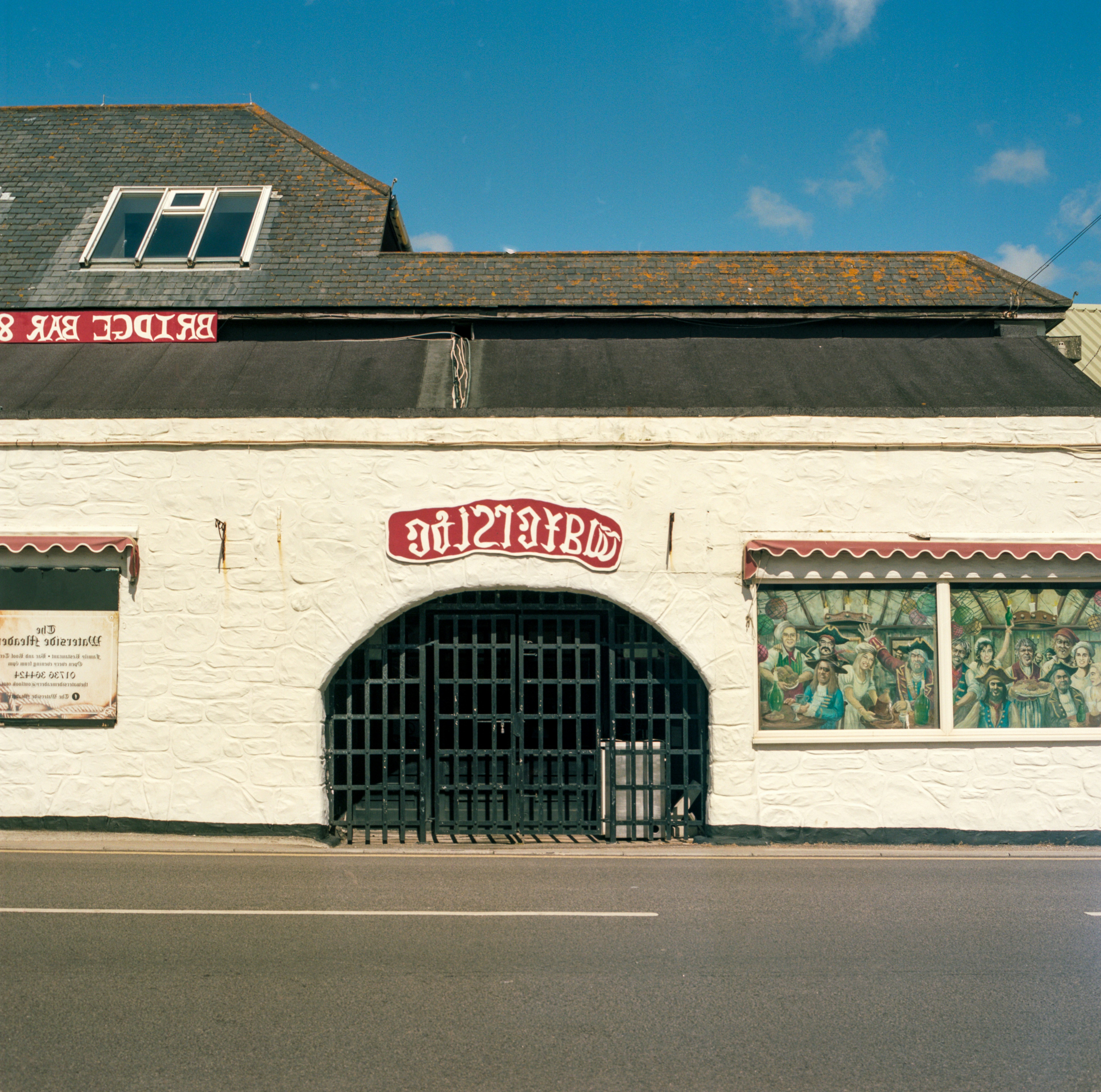 Historic building with a distinctive archway and vibrant mural, showcasing local culture and artistry. The structure's white exterior contrasts with the colorful artwork.