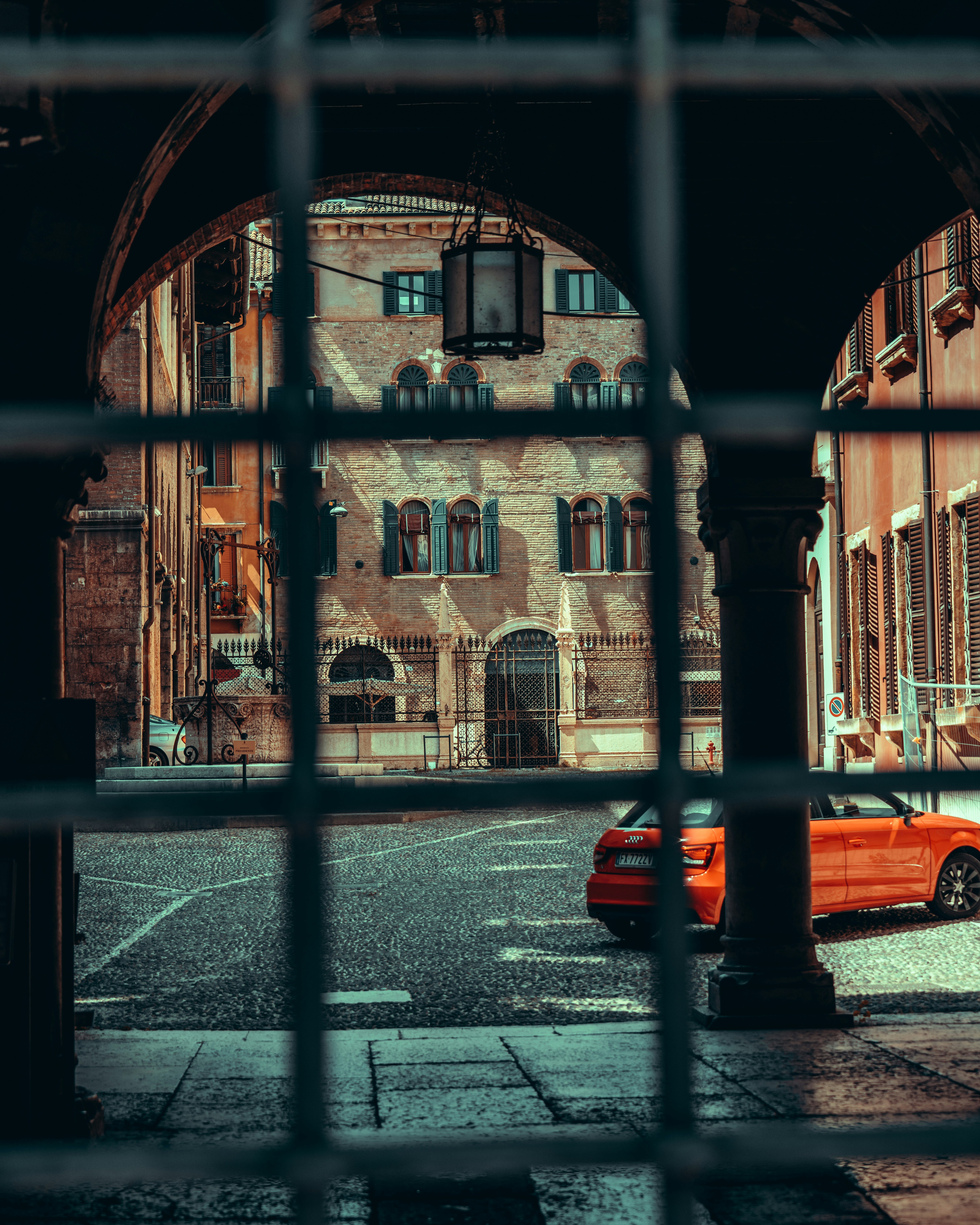 Arches Beyond the Grille: An Orange Car Framing a Historic Facade