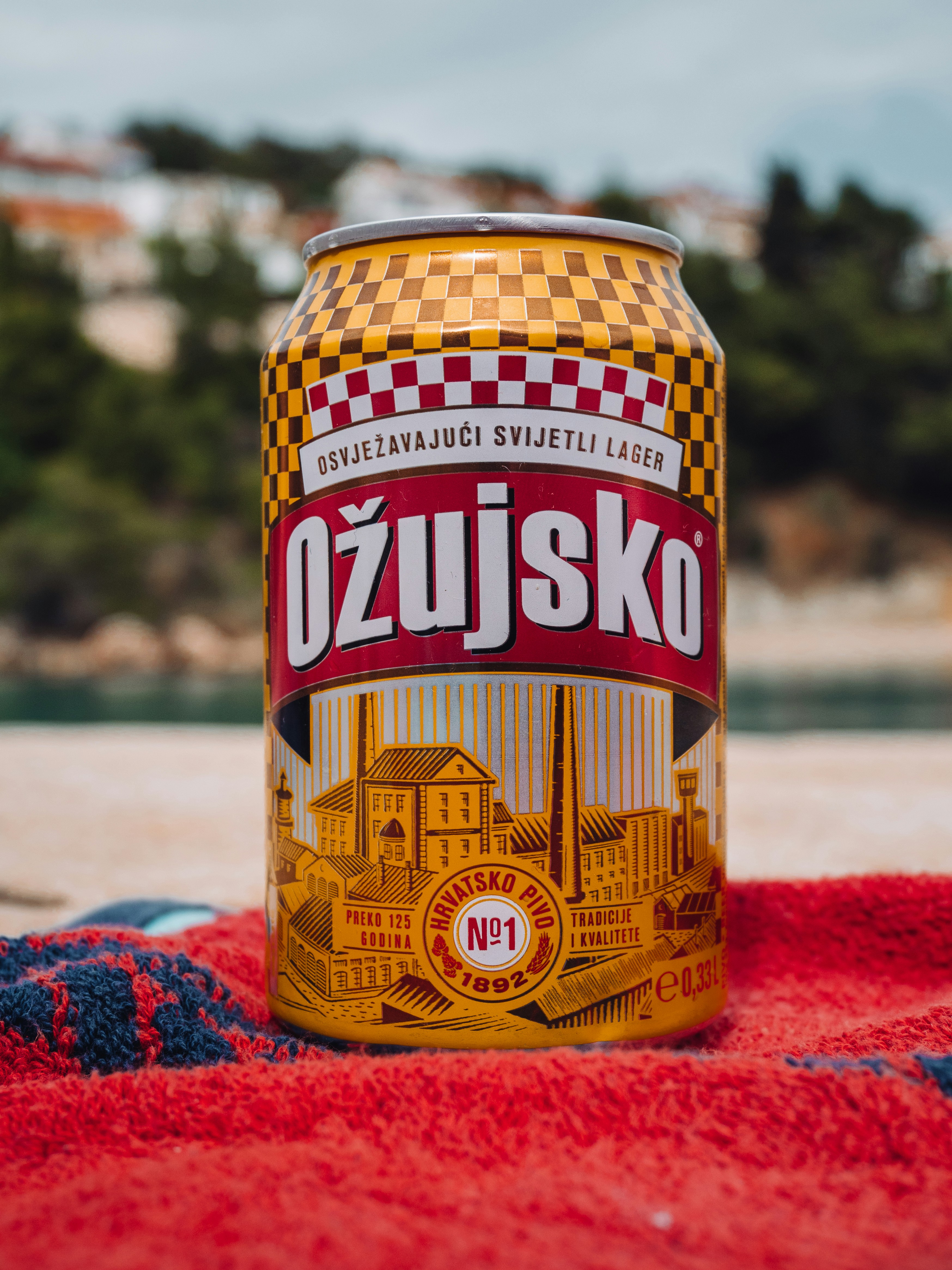 a can of beer sitting on top of a red blanket