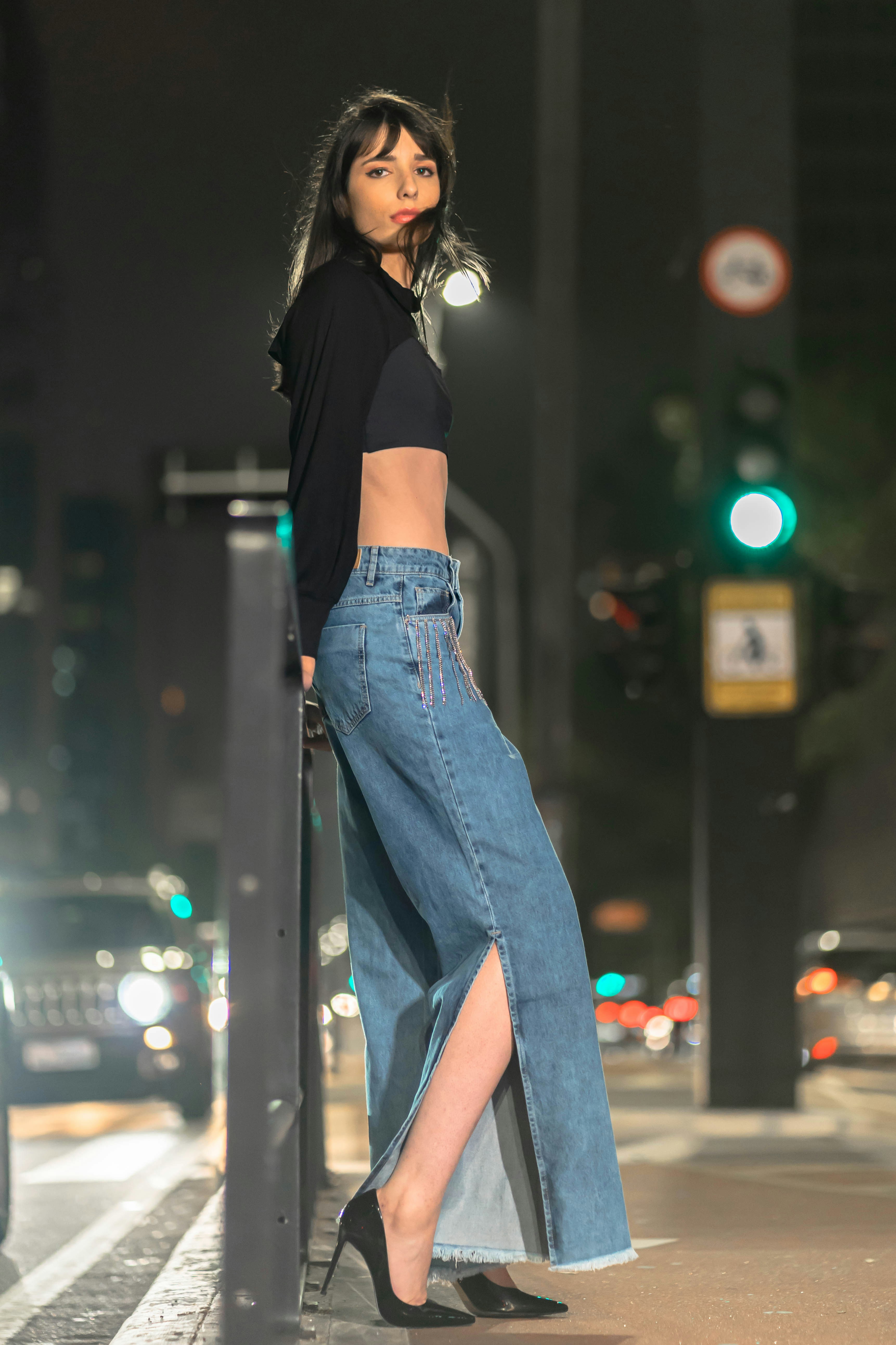 A woman leaning against a pole on a city street photo – Free Human ...