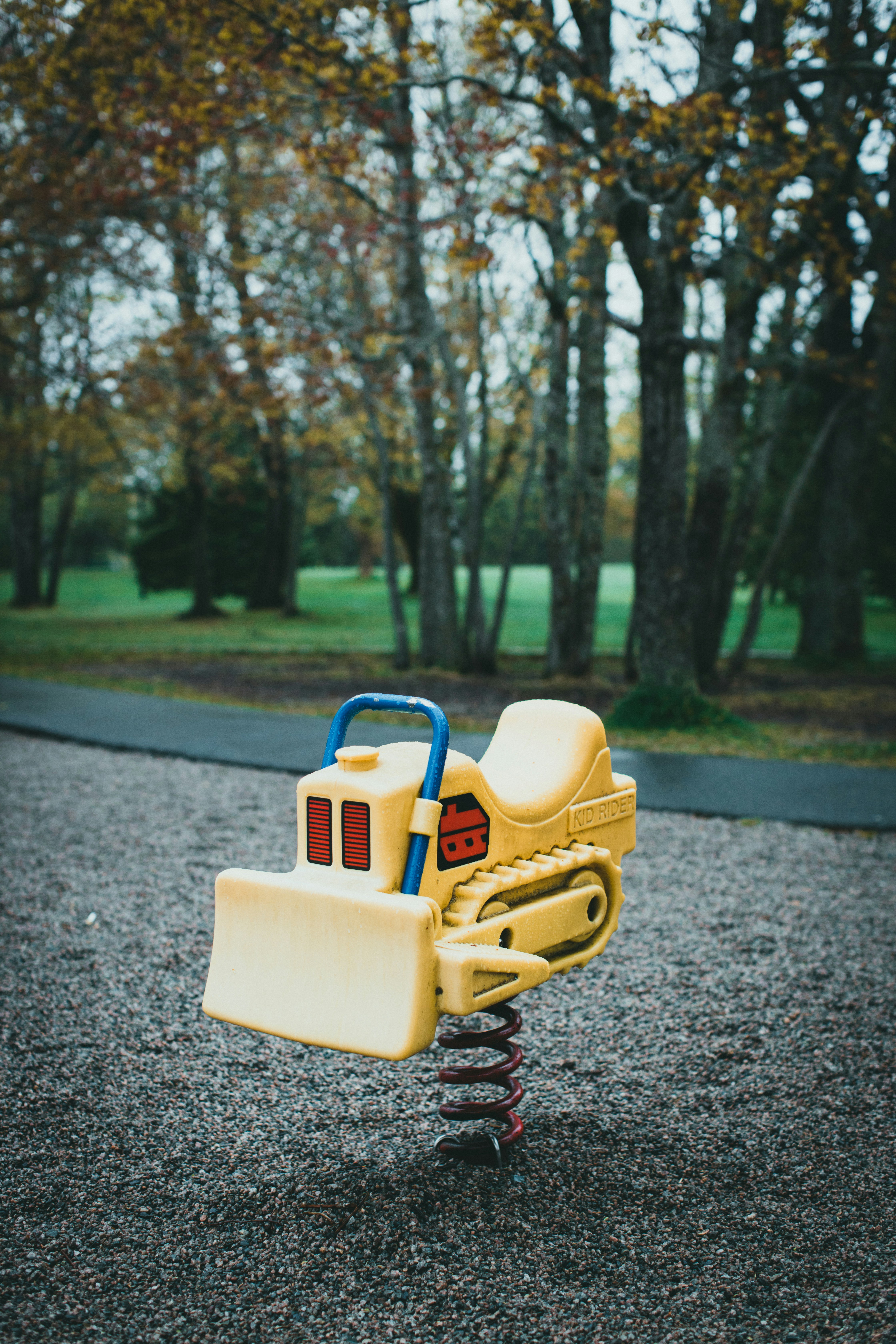 a yellow and blue toy car sitting on top of a gravel road