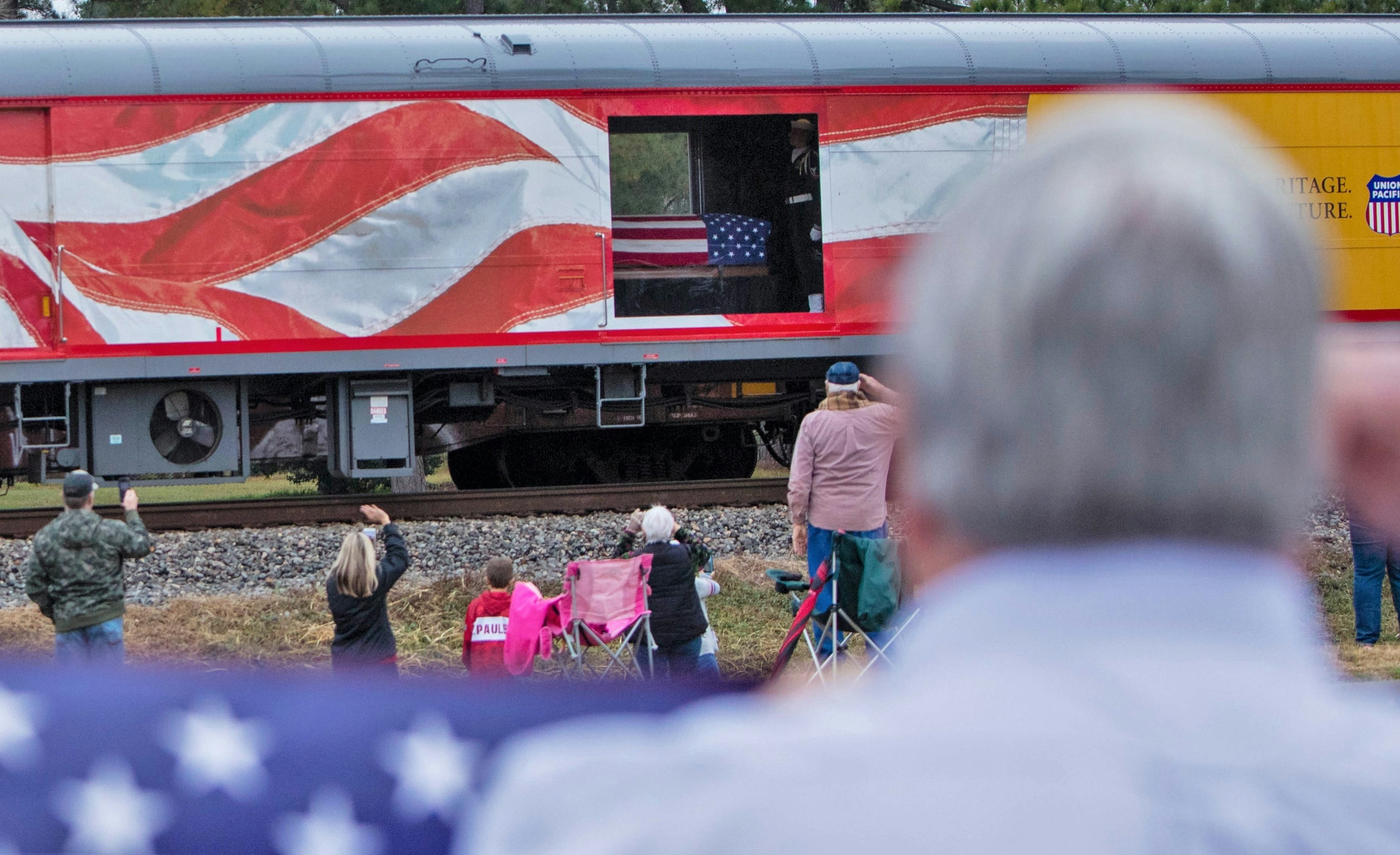 Flag Window: Spectators Watch a Patriotic Railcar Frame