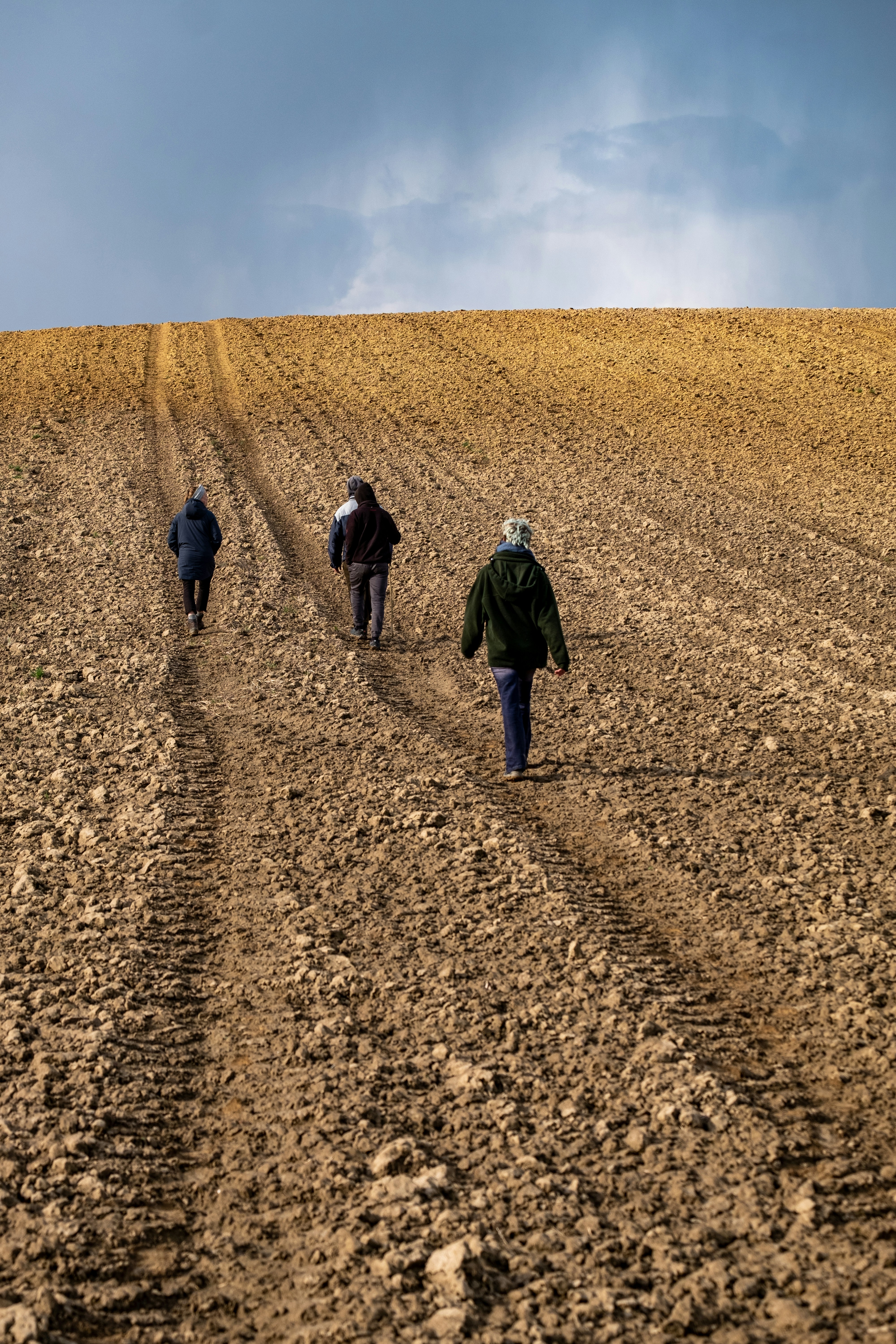 A group of people walking across a dirt field photo – Free Field Image ...