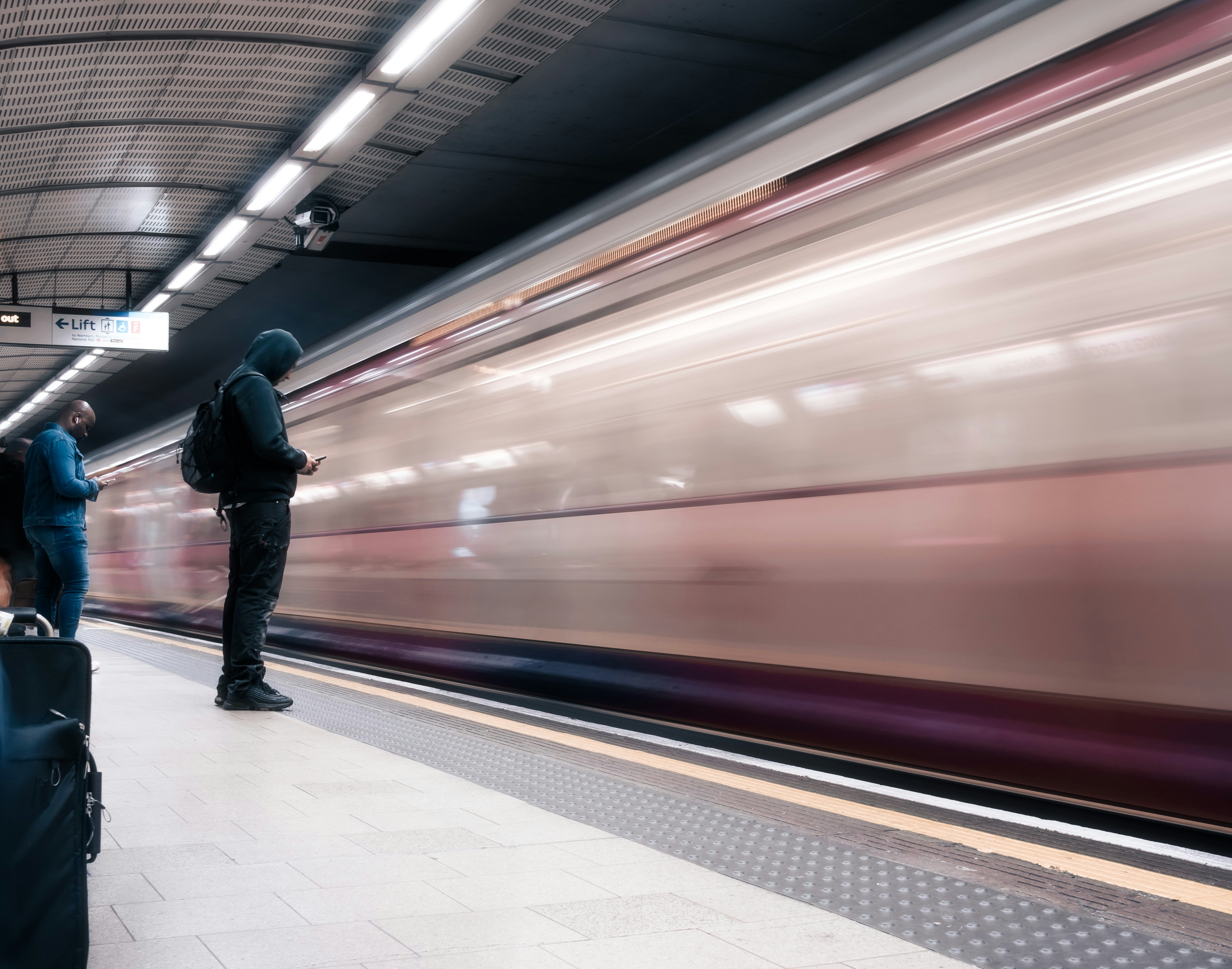 Two people waiting for a train at a train station photo – Free London ...