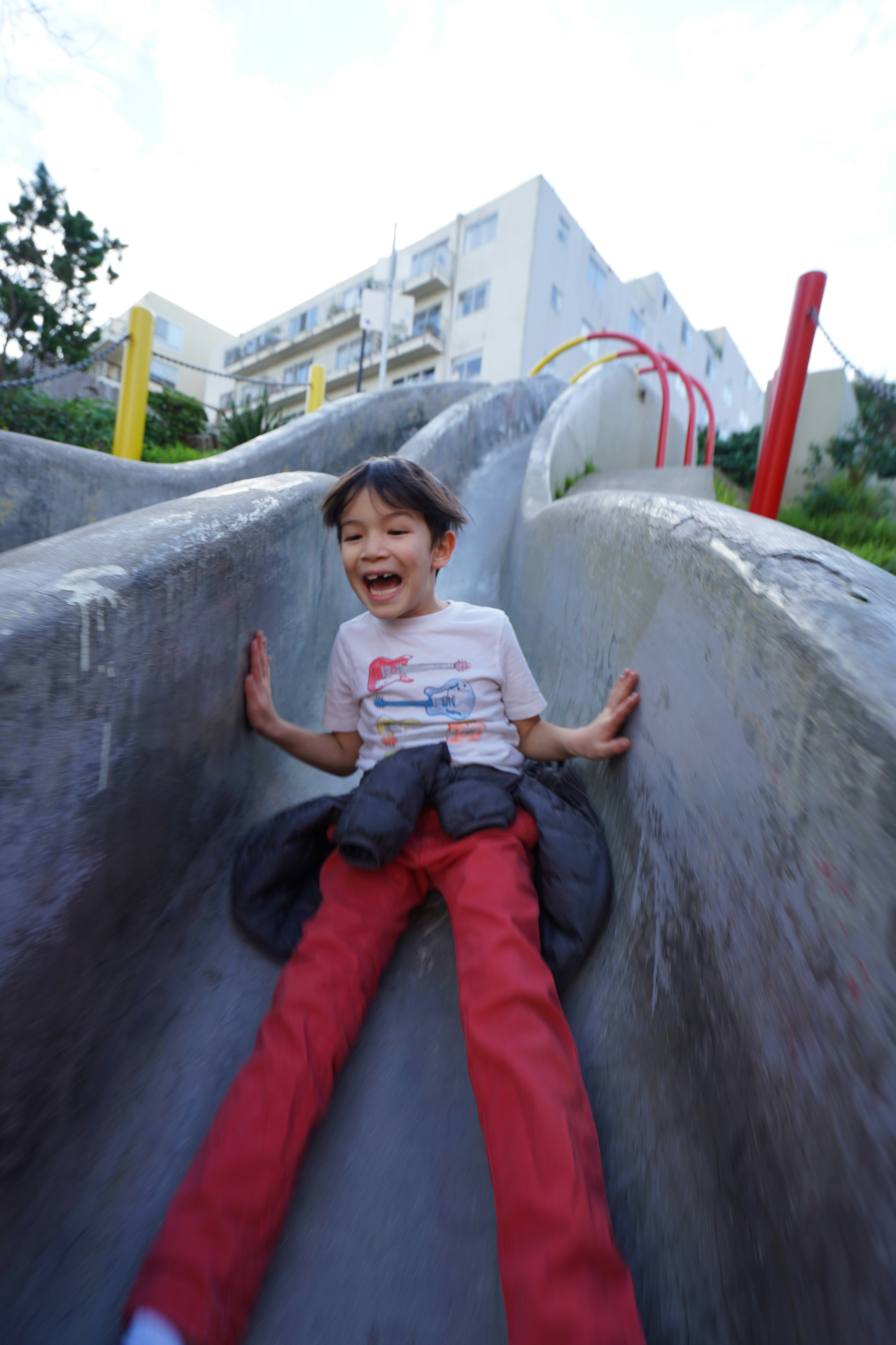 A young child sliding down a slide at a park photo – Free Slide Image ...