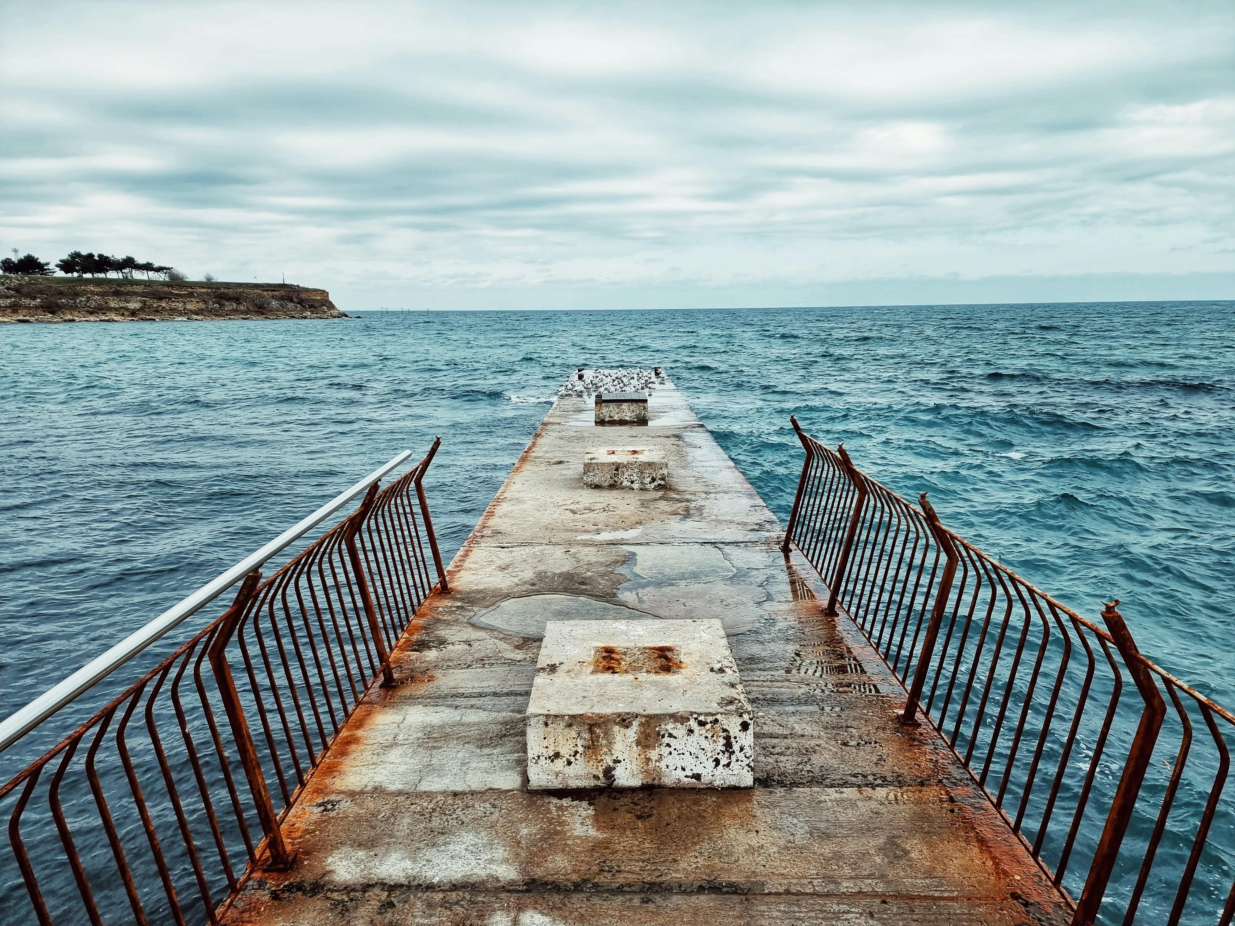 Converging Rails to the Sea: A Weathered Pier Reaches the Horizon