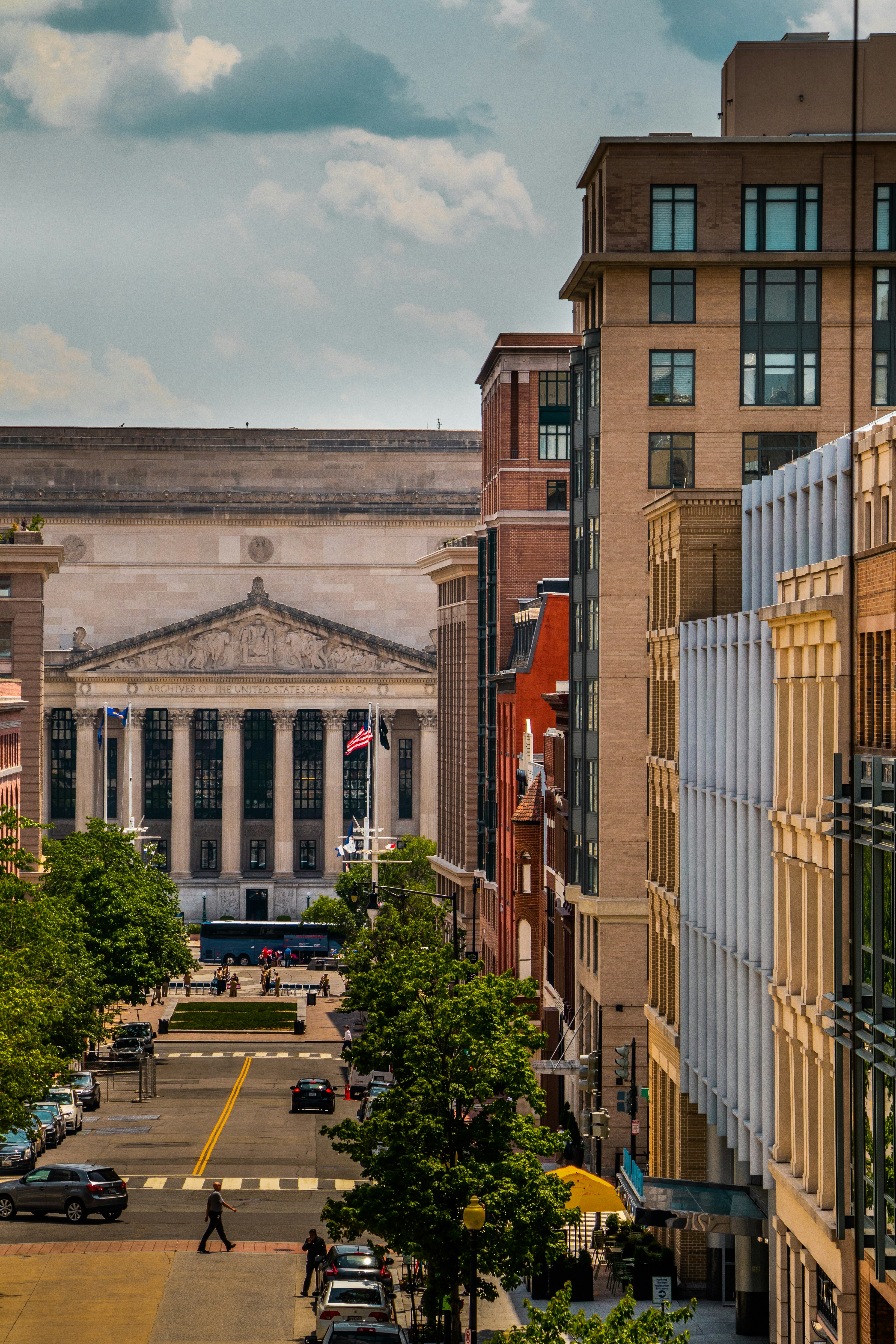 Historic building framed by modern architecture and lush greenery, showcasing a vibrant urban scene. The image highlights the blend of old and new in city design.