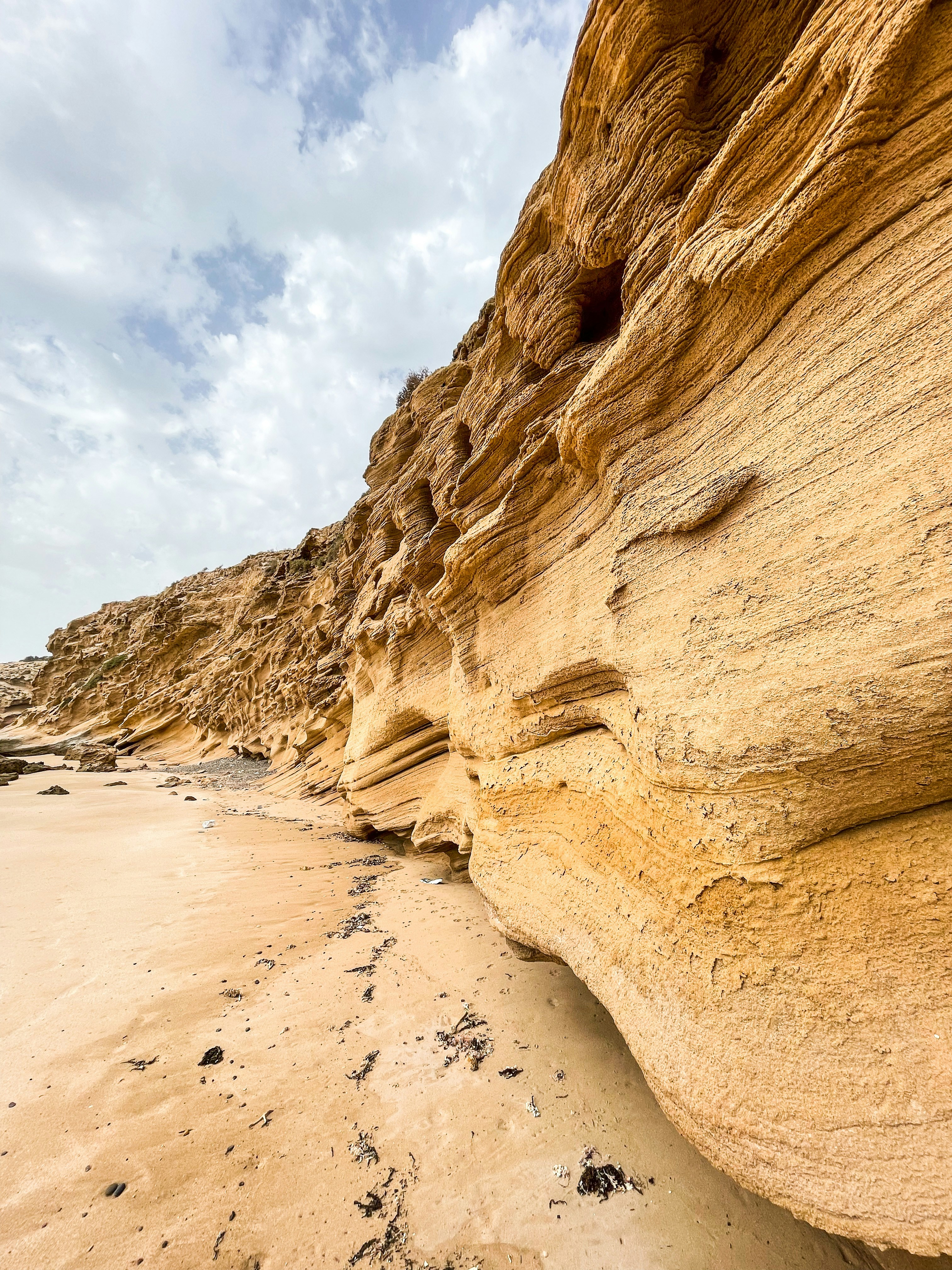 A sandy beach next to a cliff under a cloudy sky photo – Free Morocco ...