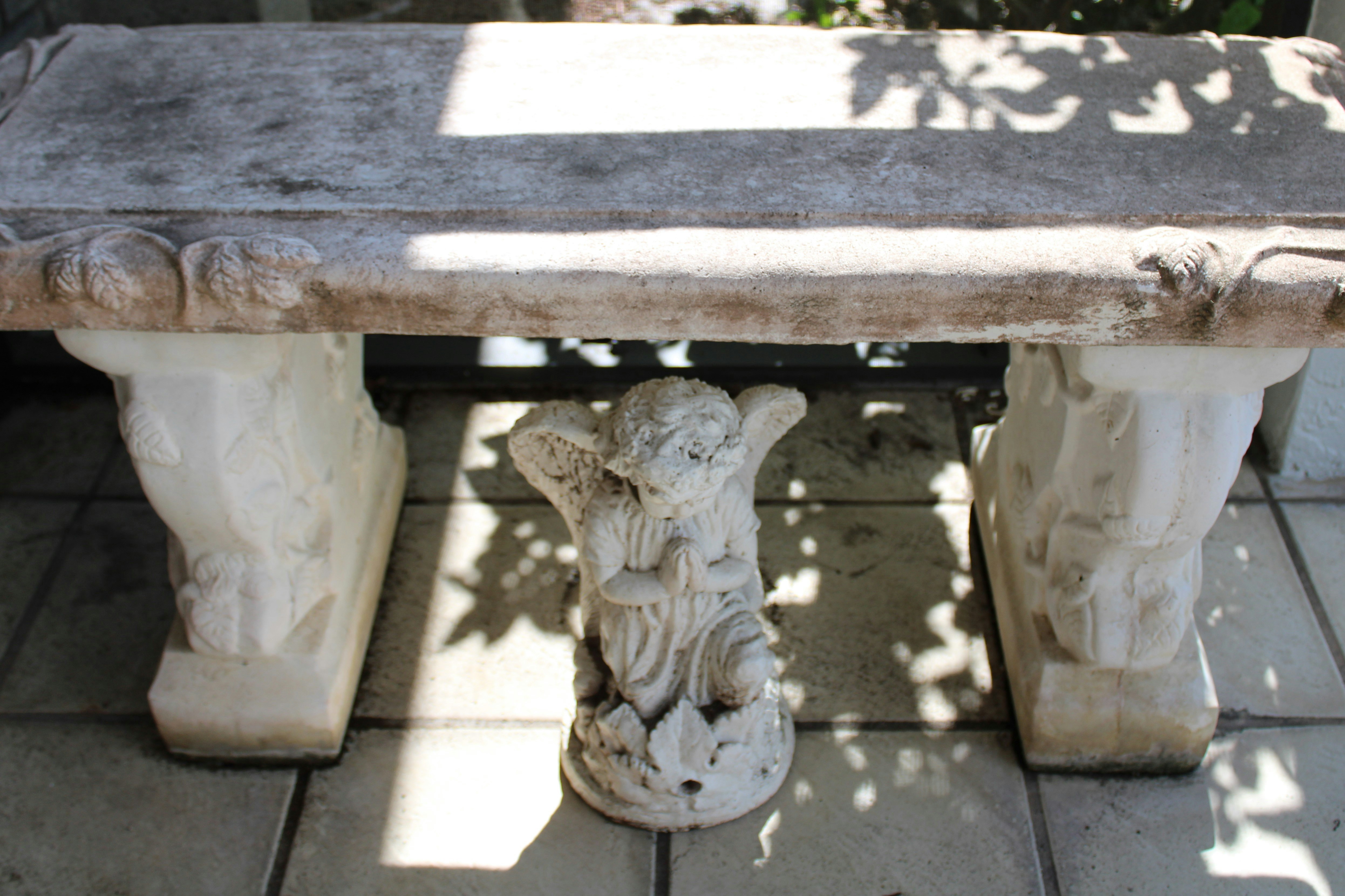 Sunlit Cherub Under a Carved Stone Bench
