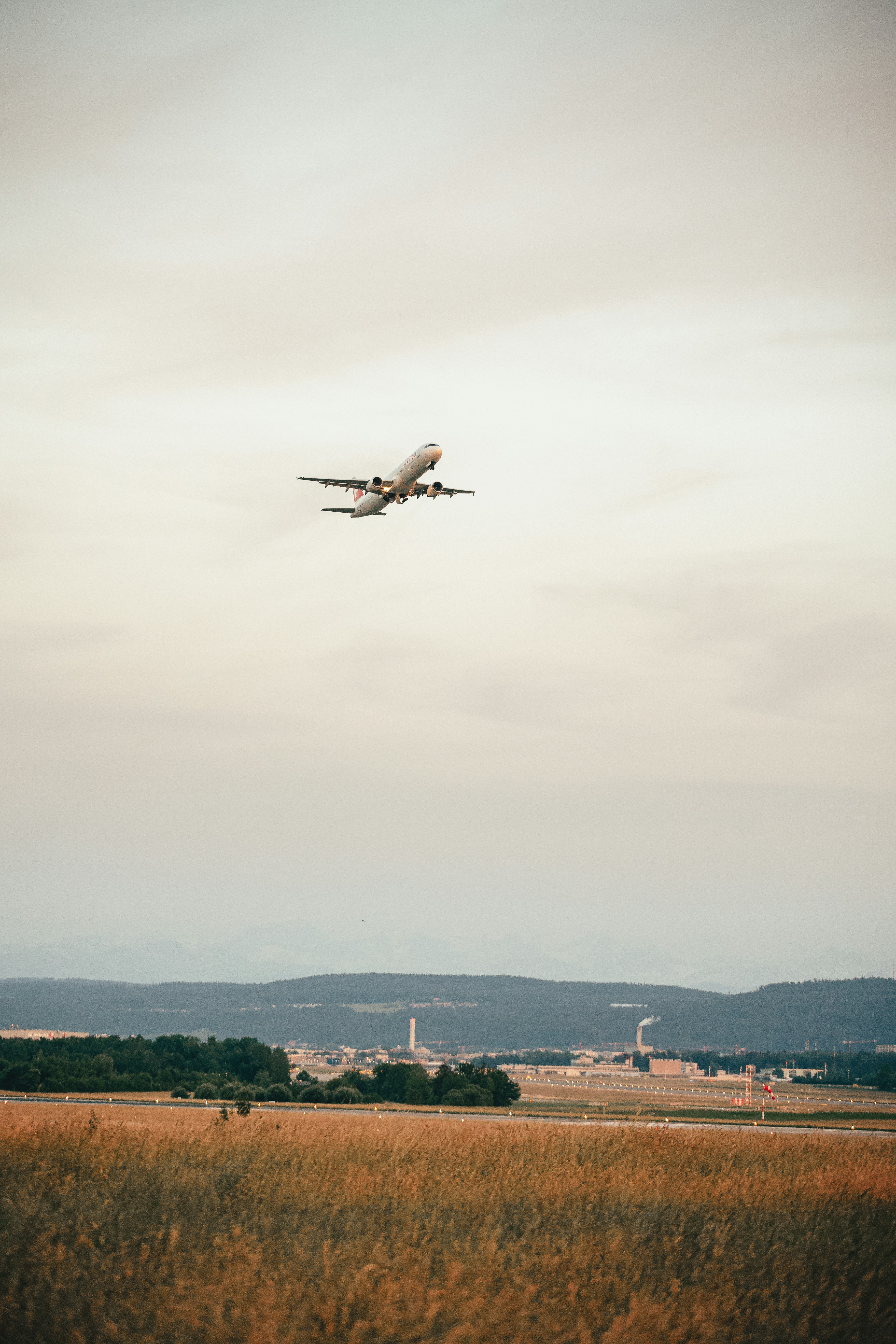 Commercial airplane ascending against a backdrop of distant mountains and a sprawling landscape. The scene captures the essence of travel and adventure.