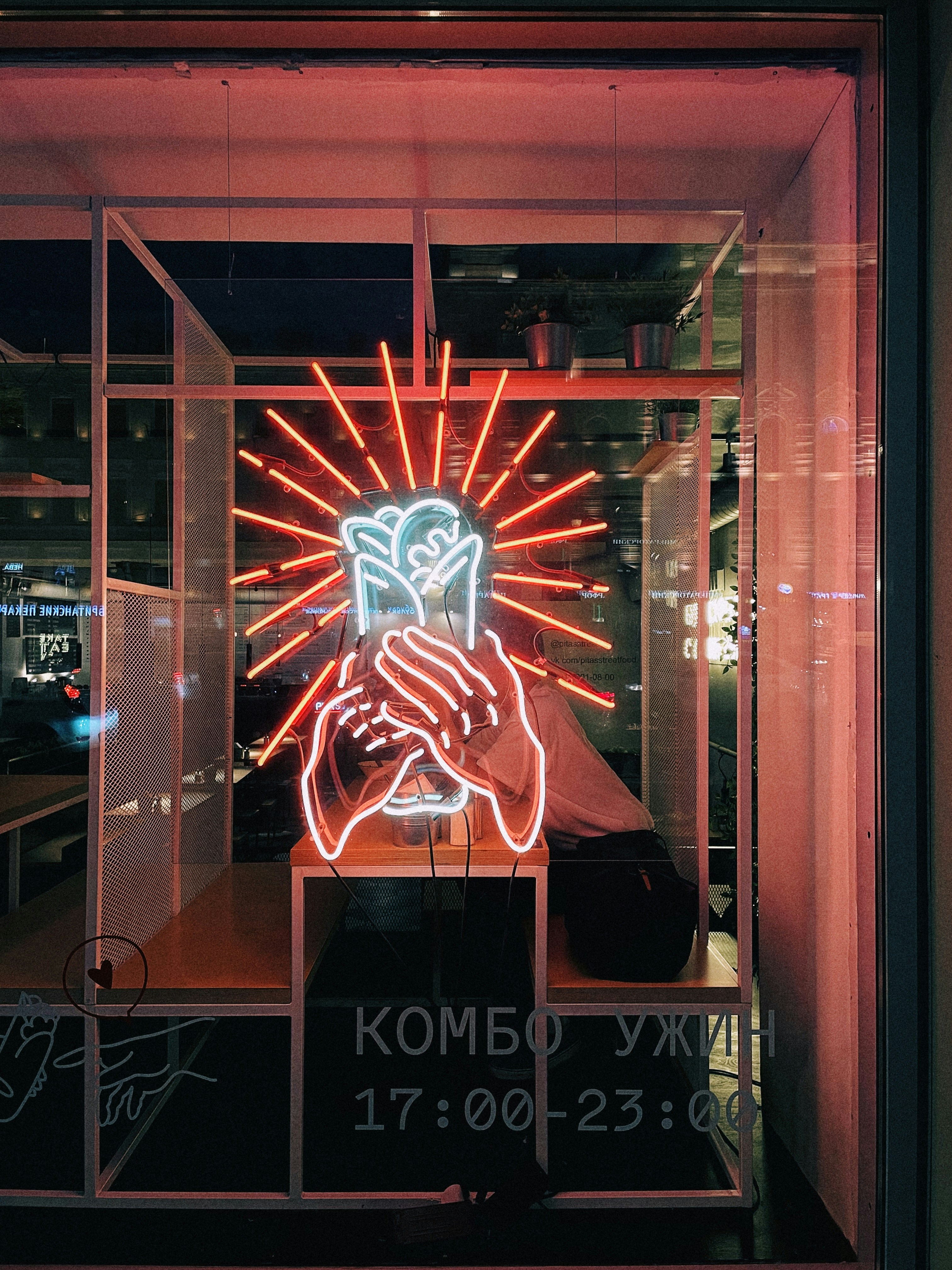 Neon Embrace: Hands Cradling Light in a Glass-Front Night Display