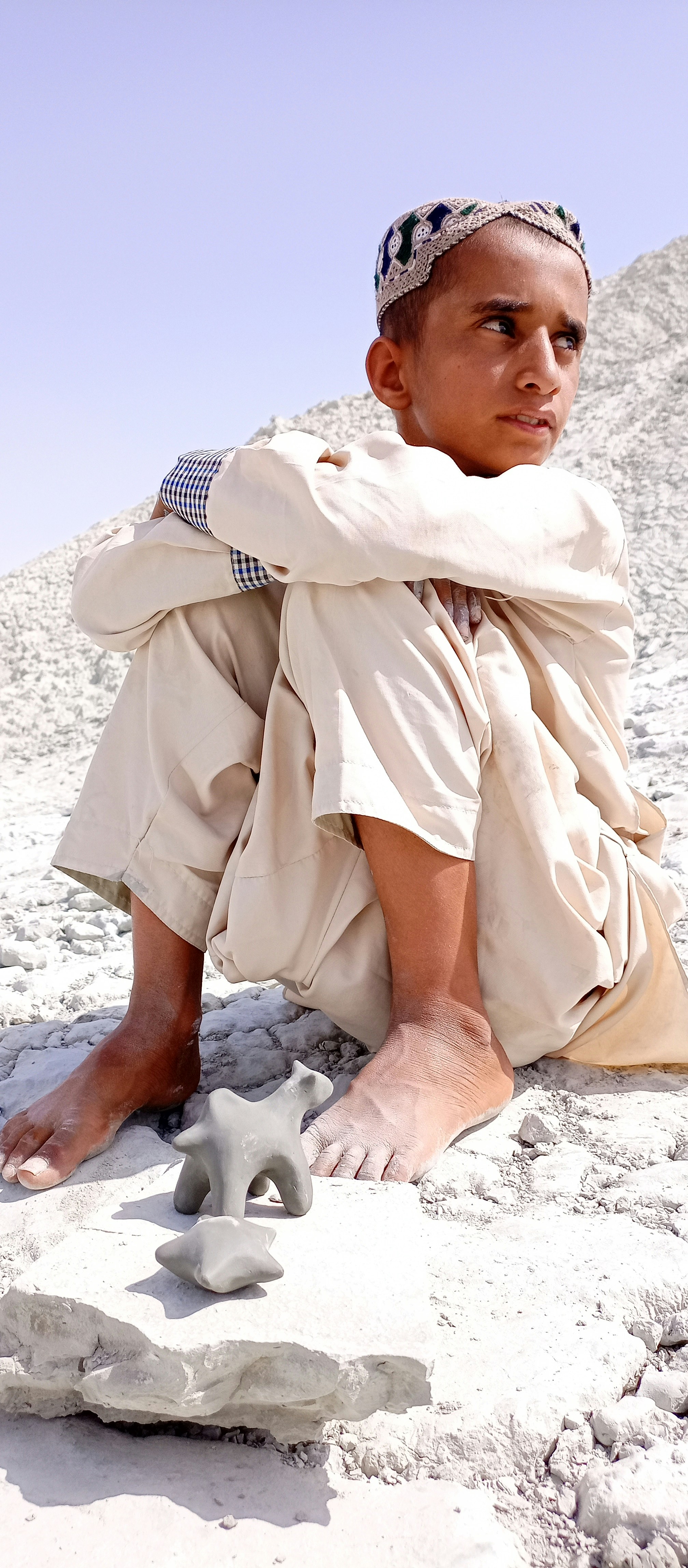 Desert Portrait: Boy in White Attire Among Chalky Peaks