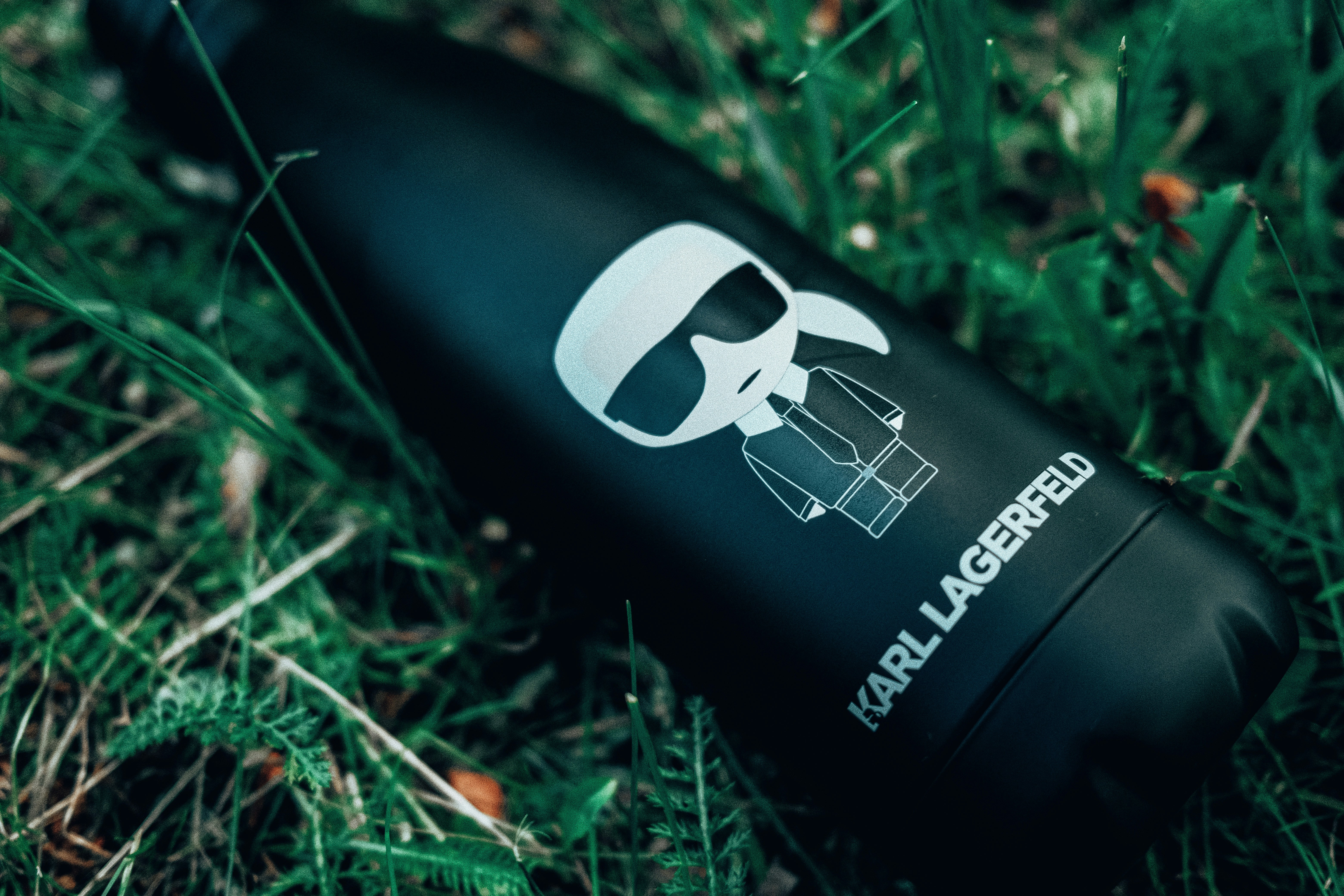 Foto Una botella de agua negra sentada en la hierba – Imagen ...
