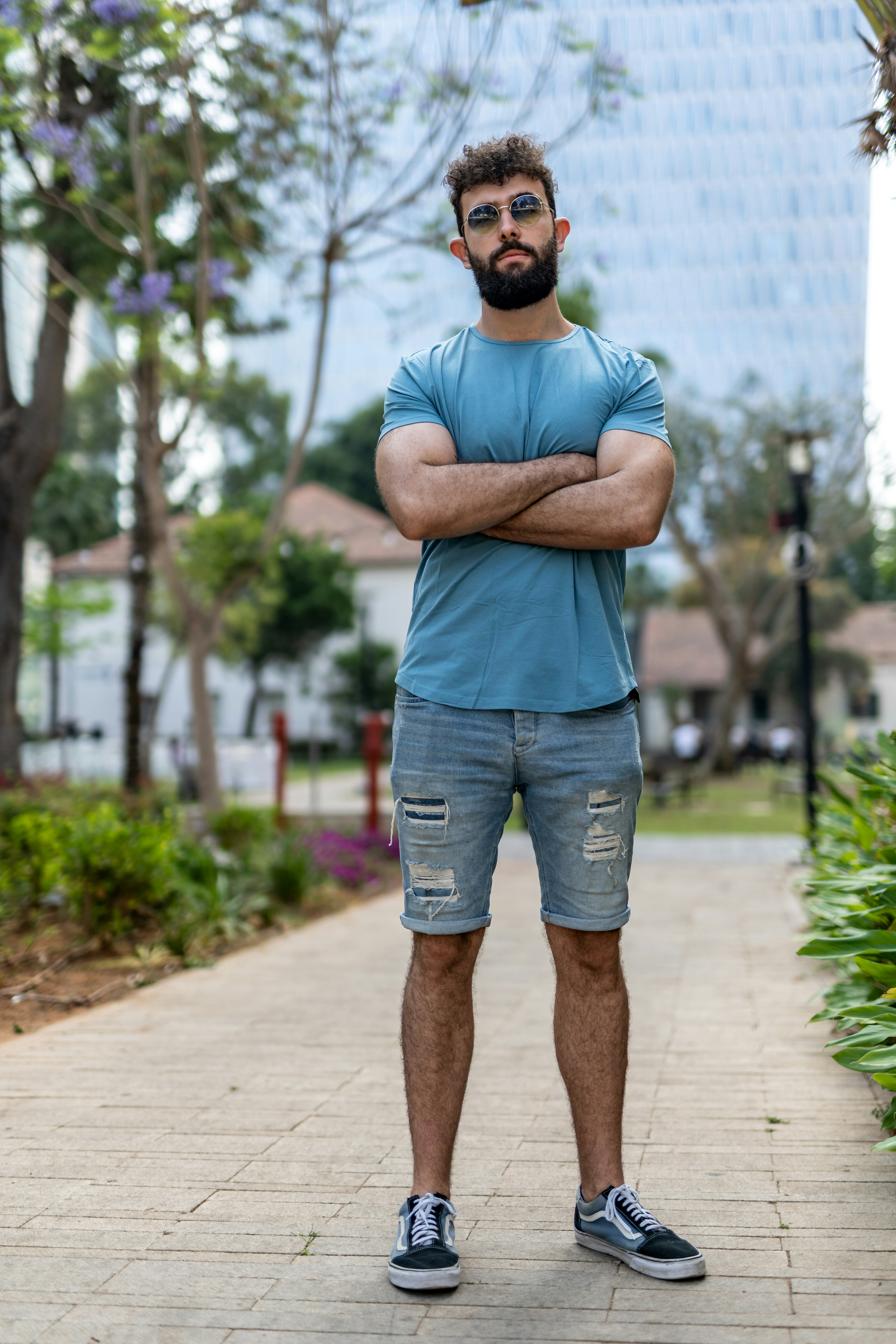 A man standing on a sidewalk with his arms crossed photo – Free Blue ...