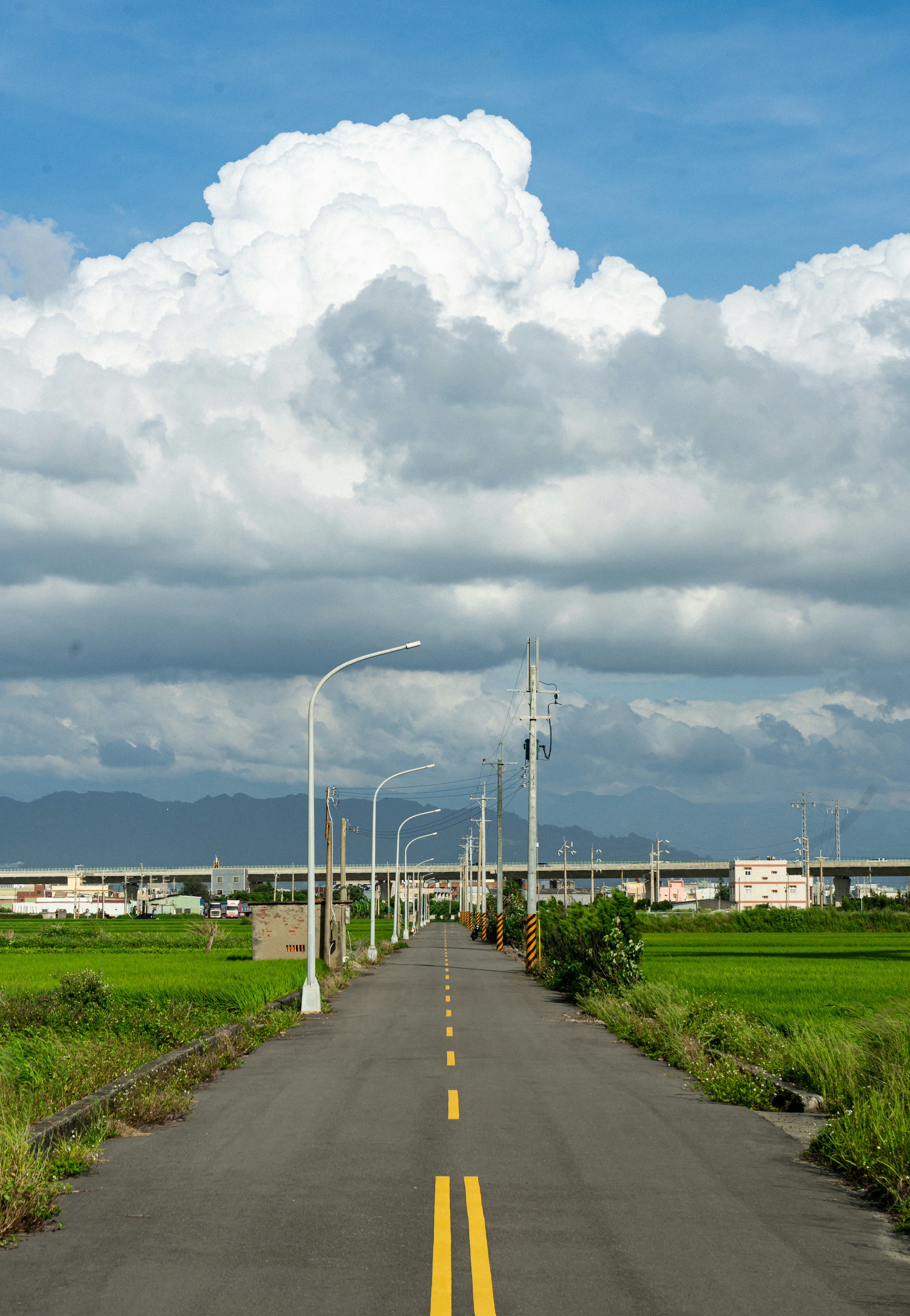 a long empty road with a sky filled with clouds