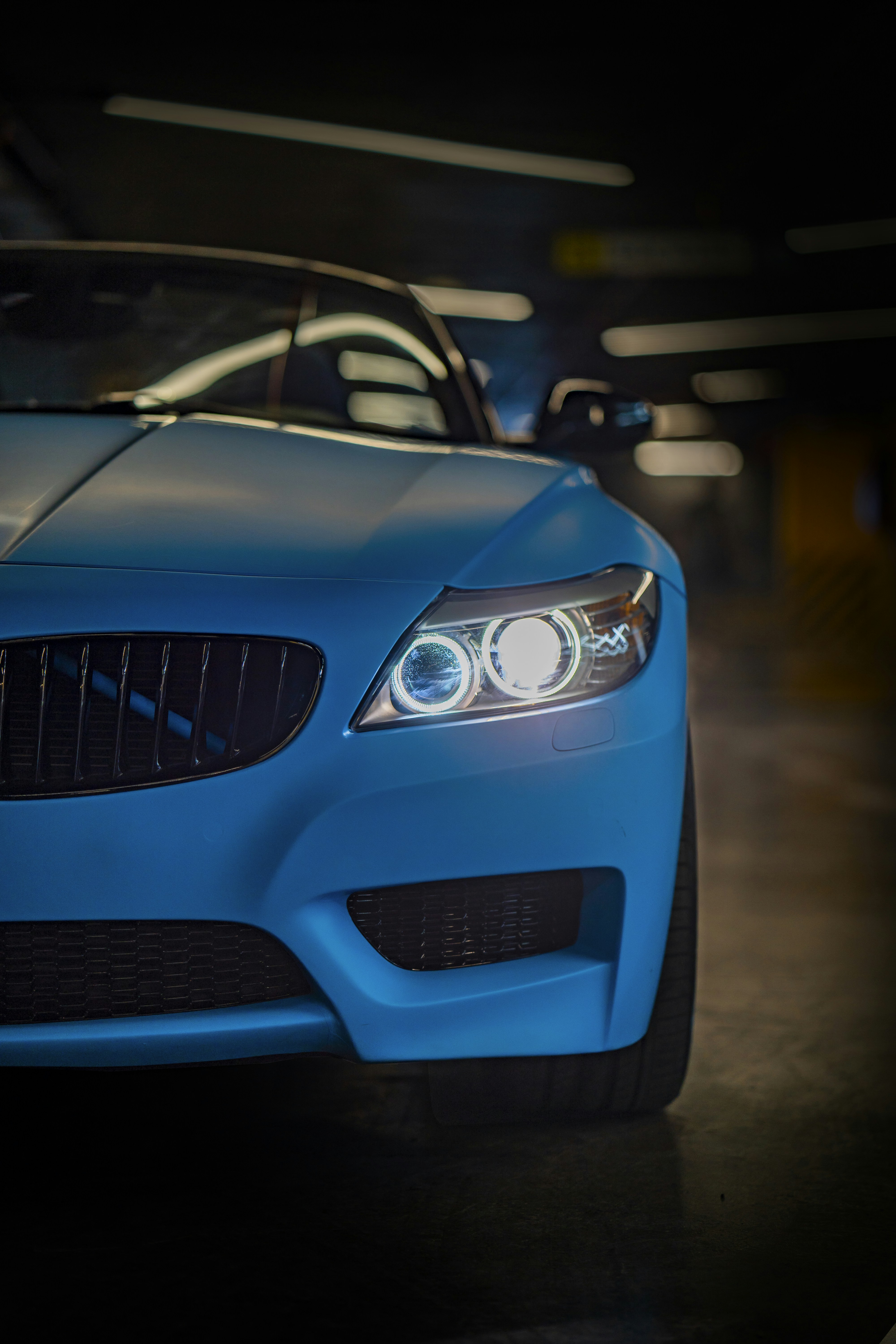 Blue Frontline: Halo Headlights Illuminate a Quiet Garage Portrait