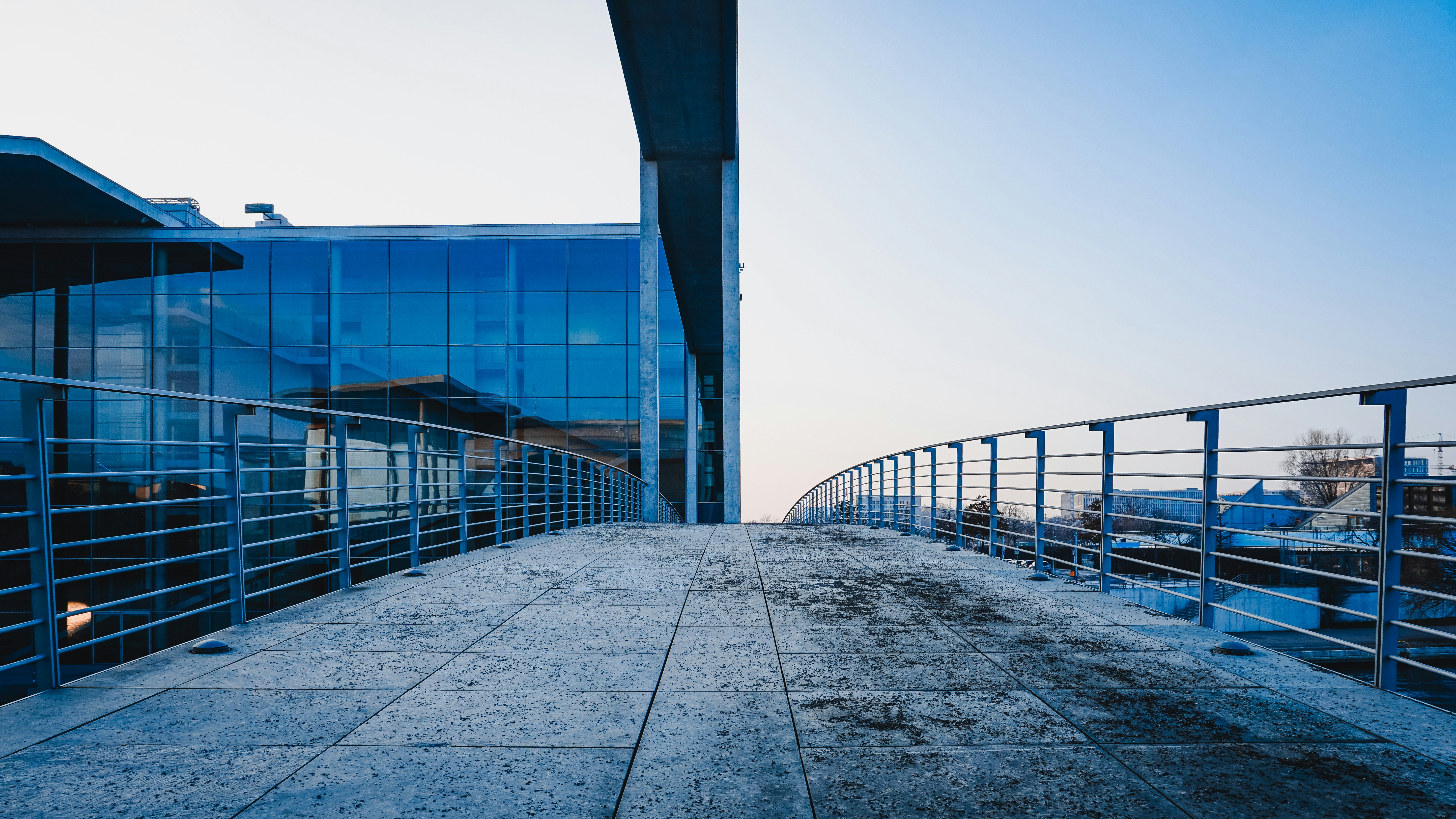 A walkway leading to a building with a large glass window photo – Free ...