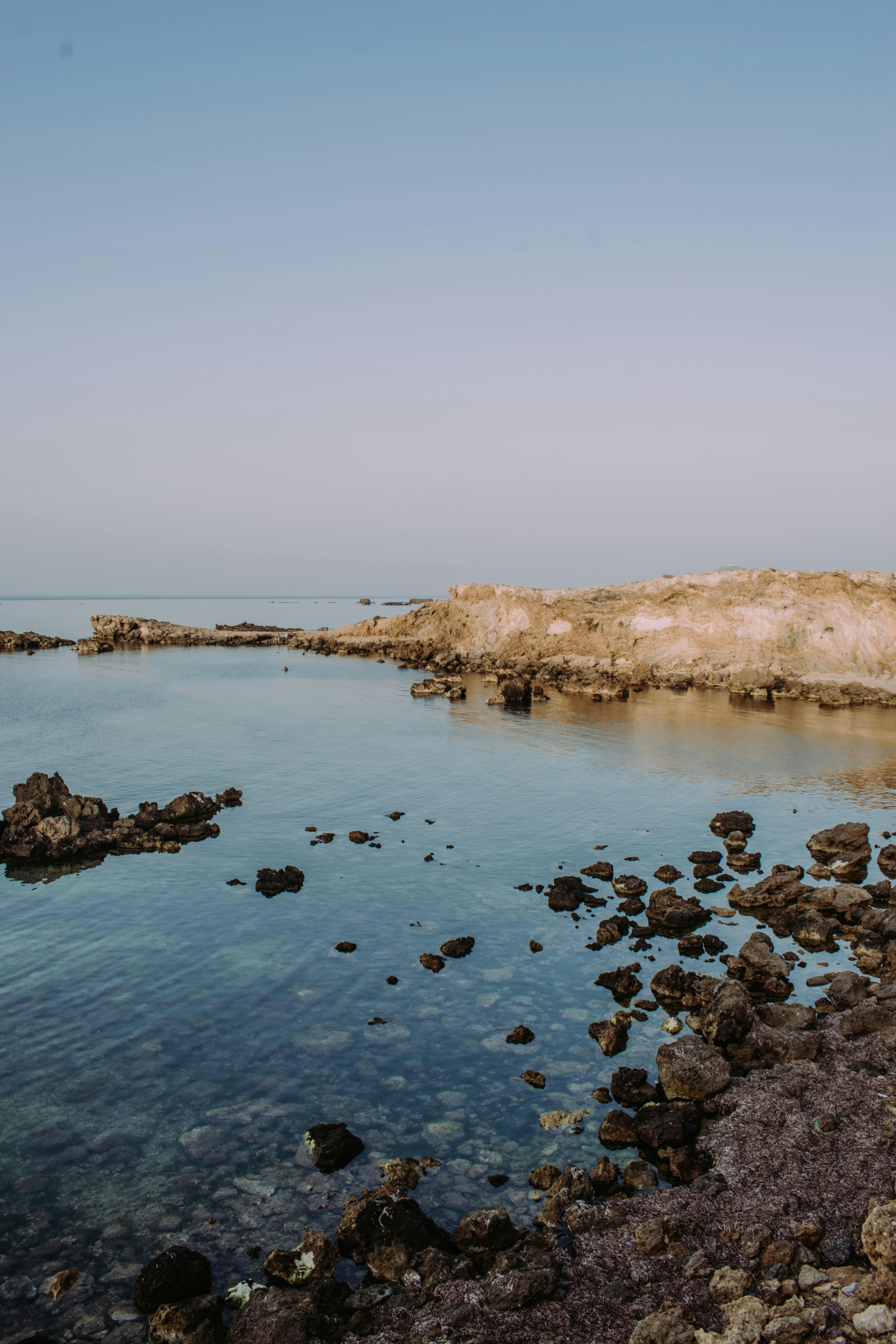 A large body of water surrounded by rocks photo – Free Promontory Image ...