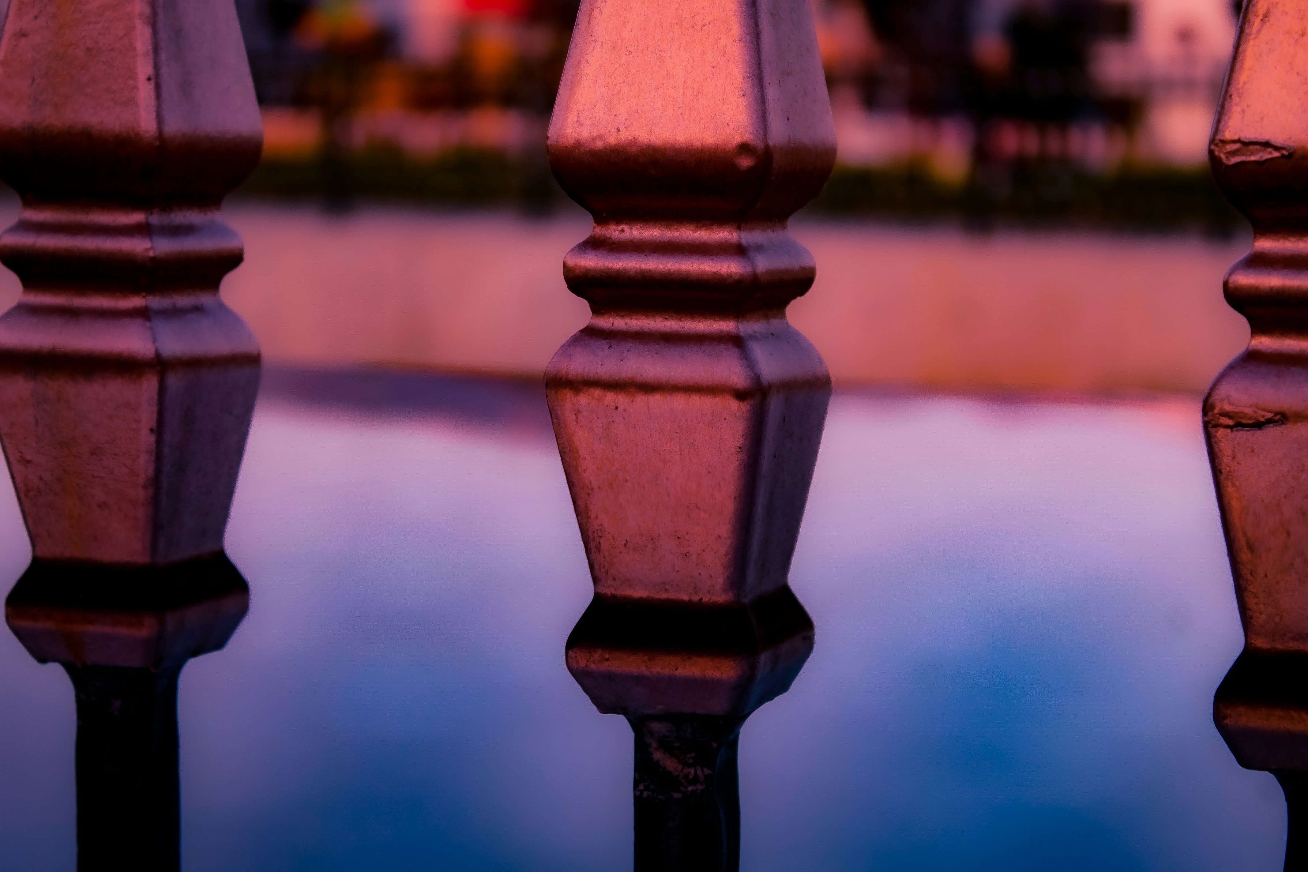 Rusted balustrade silhouettes above a mirrored canal at twilight