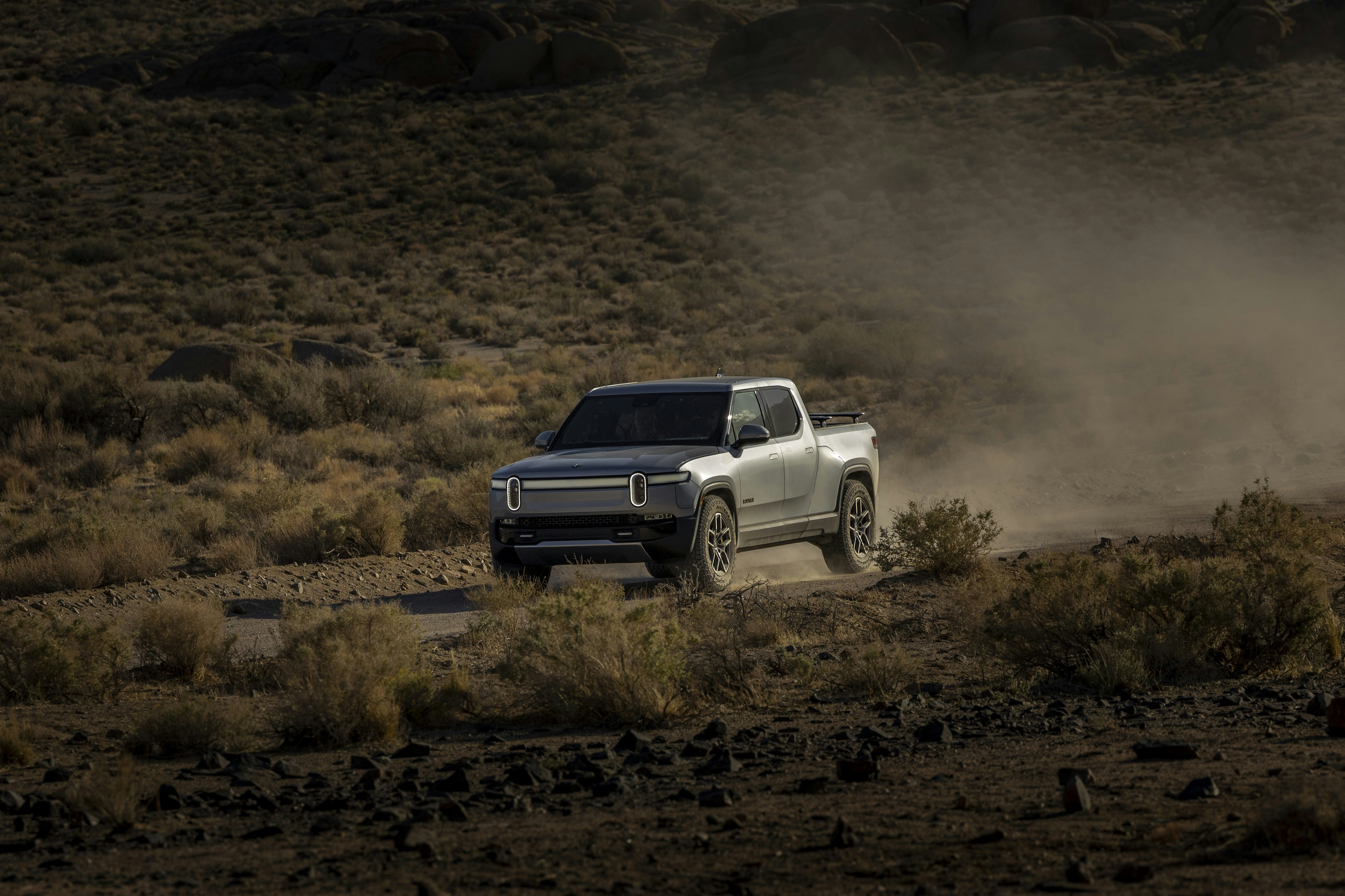 A white truck driving down a dirt road photo – Free Rivian truck Image ...