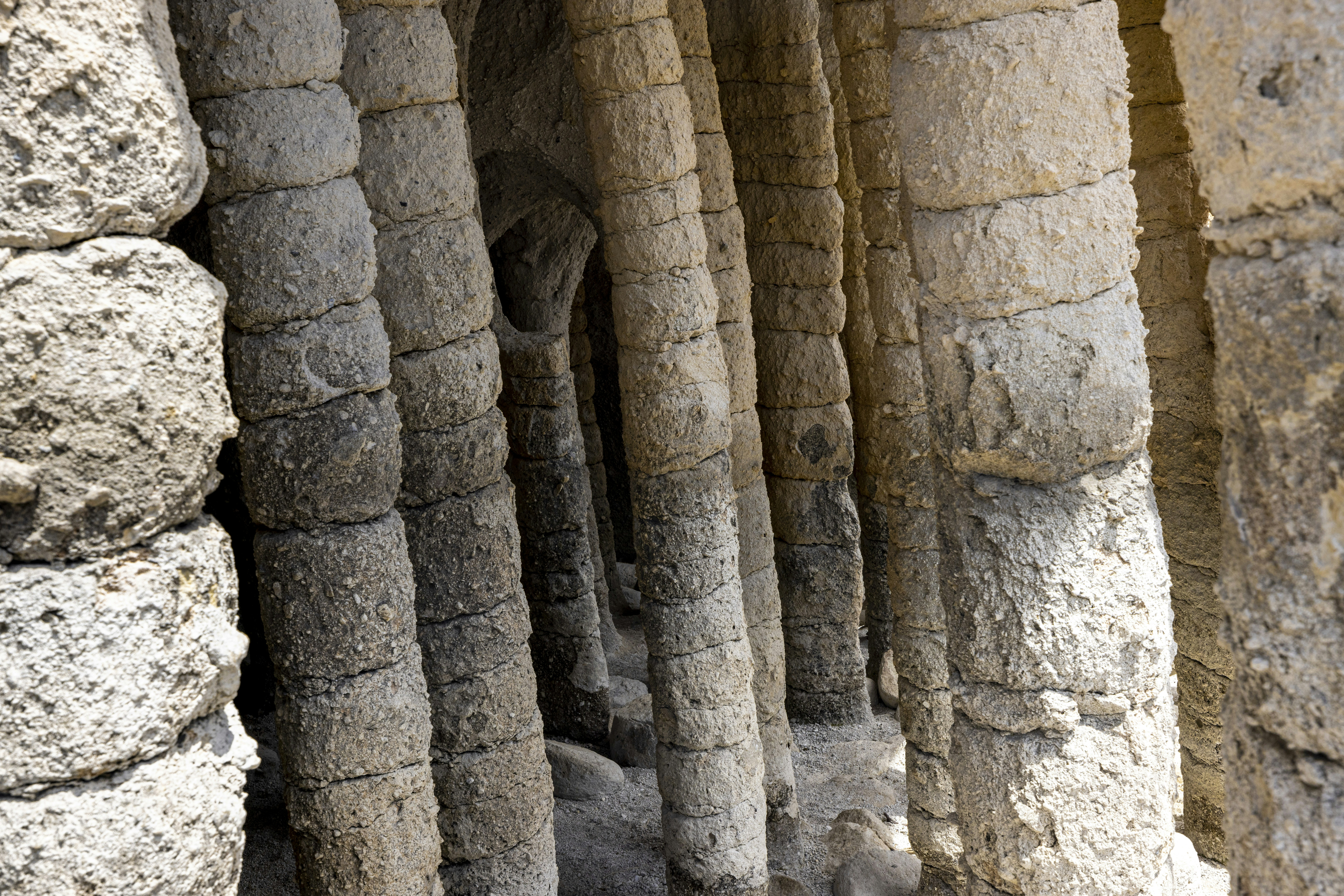 Intricate stone columns create a mesmerizing corridor, showcasing the artistry of ancient craftsmanship in a sunlit setting.