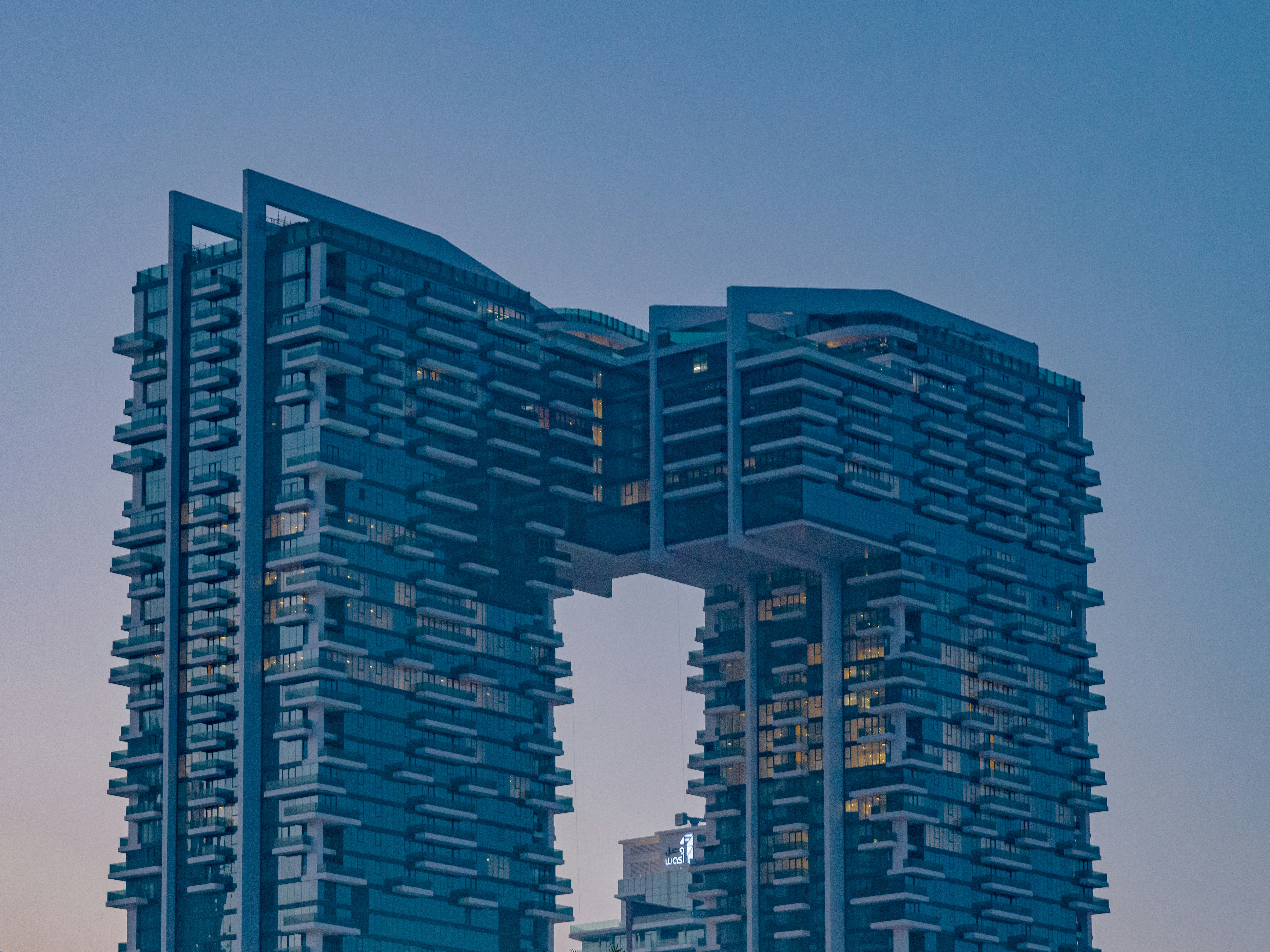 Modern skyscraper with a unique design, featuring an open section in the middle against a twilight sky.