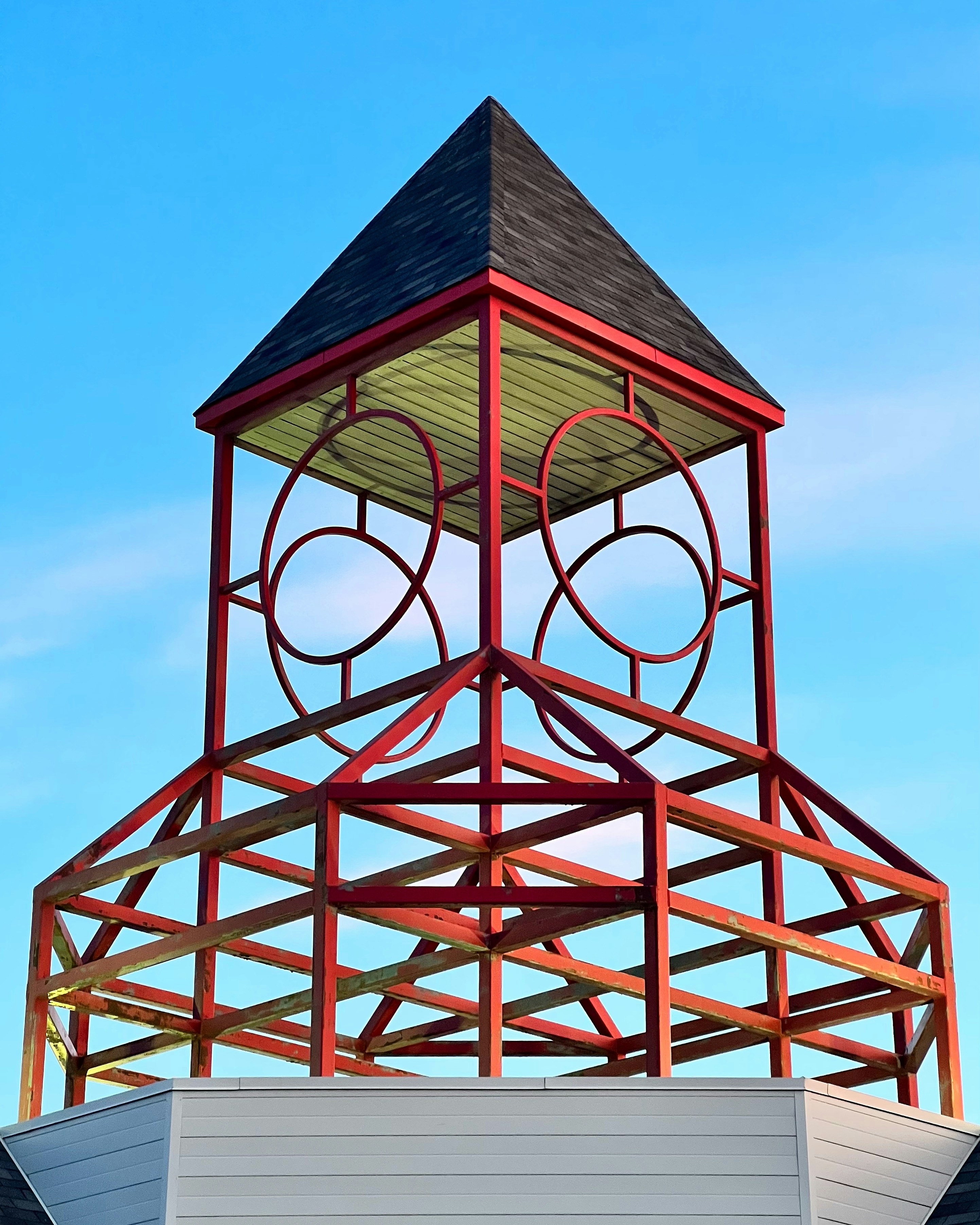 Crimson Lattice Spire Rising Over a Roofline