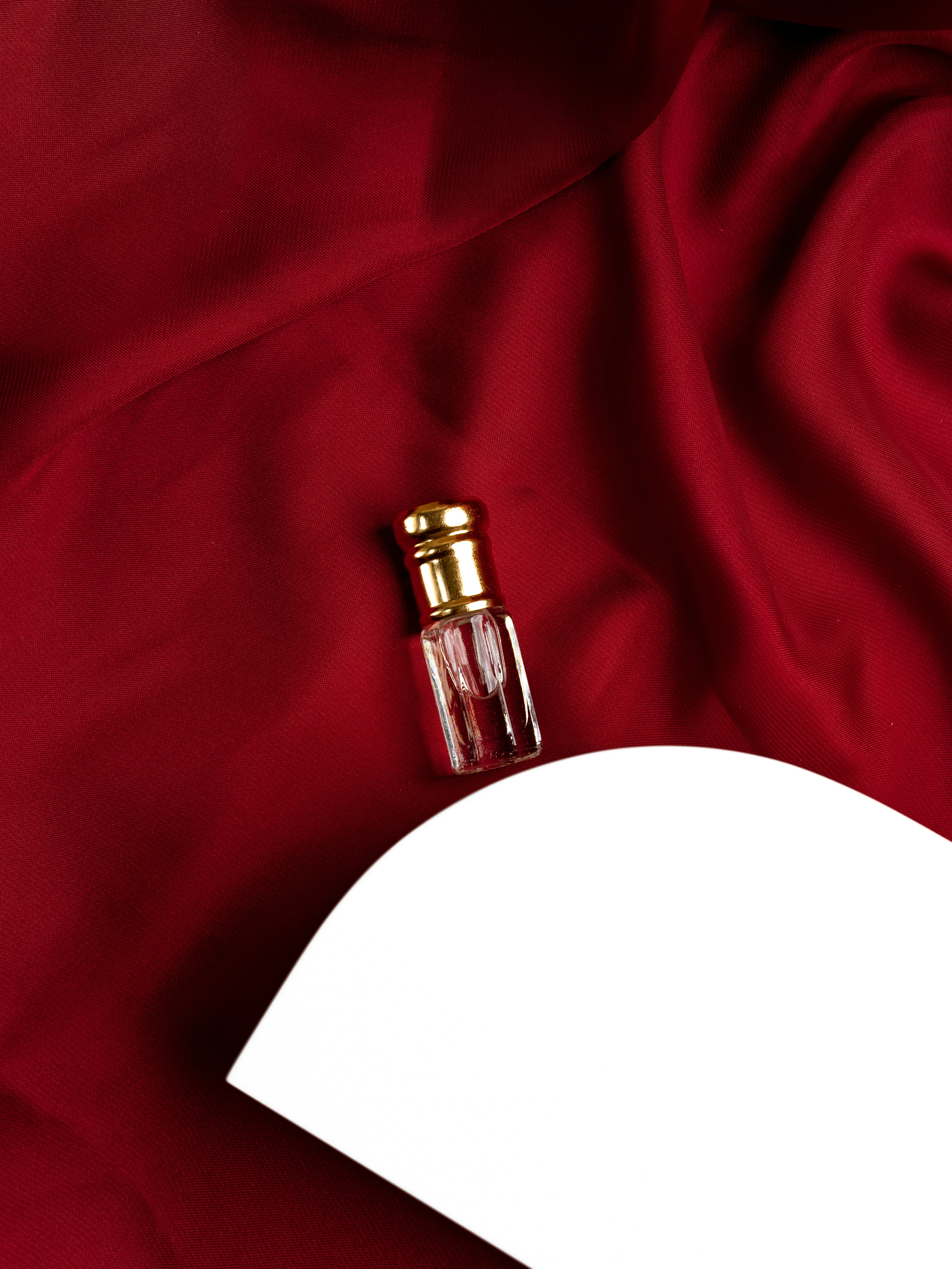 A bottle of perfume sitting on top of a red cloth photo – Free Brown ...