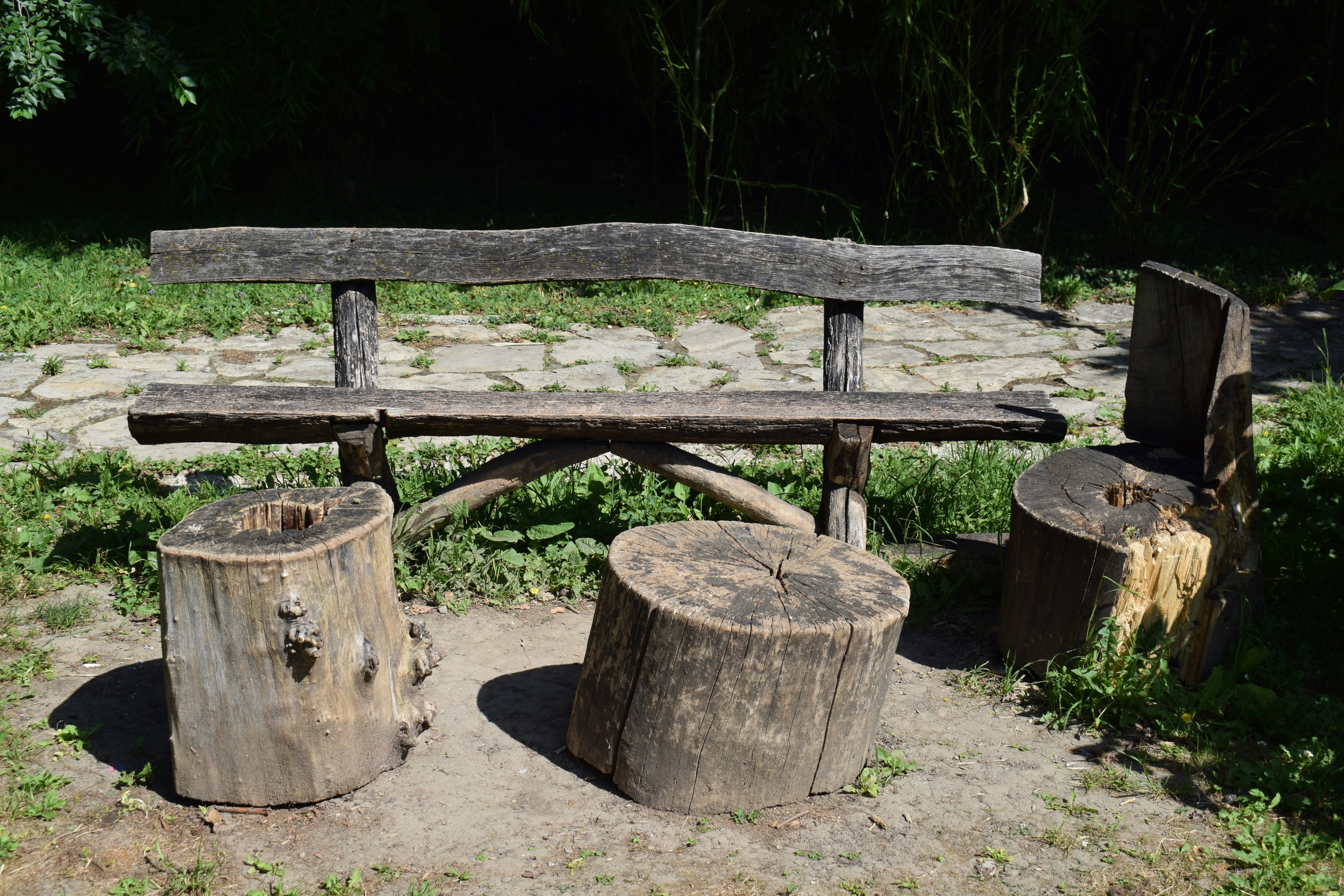 a wooden bench sitting next to two stumps