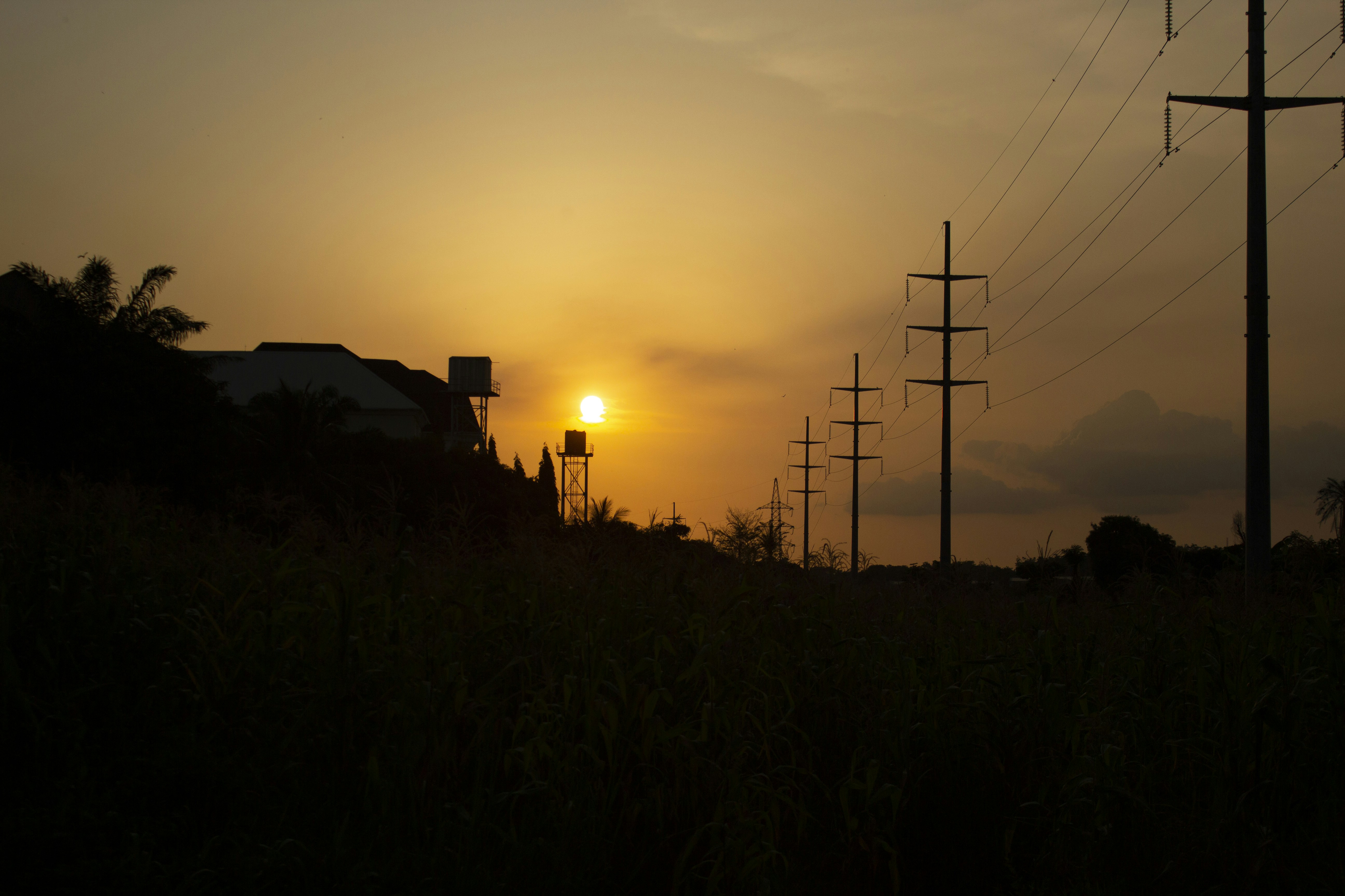 the sun is setting in the distance behind power lines