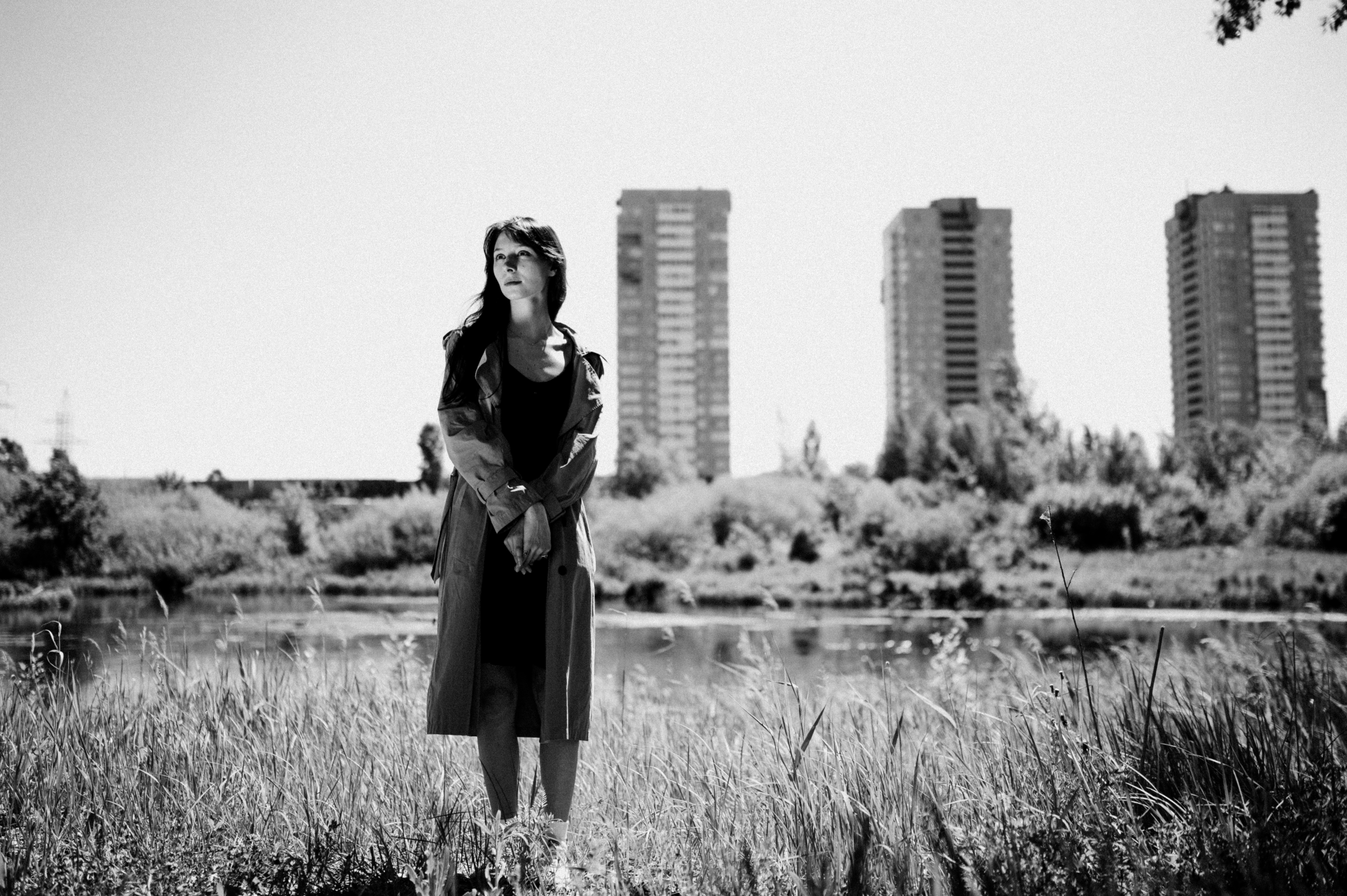 Midfield Quiet: A lone figure in a windswept field beneath distant towers