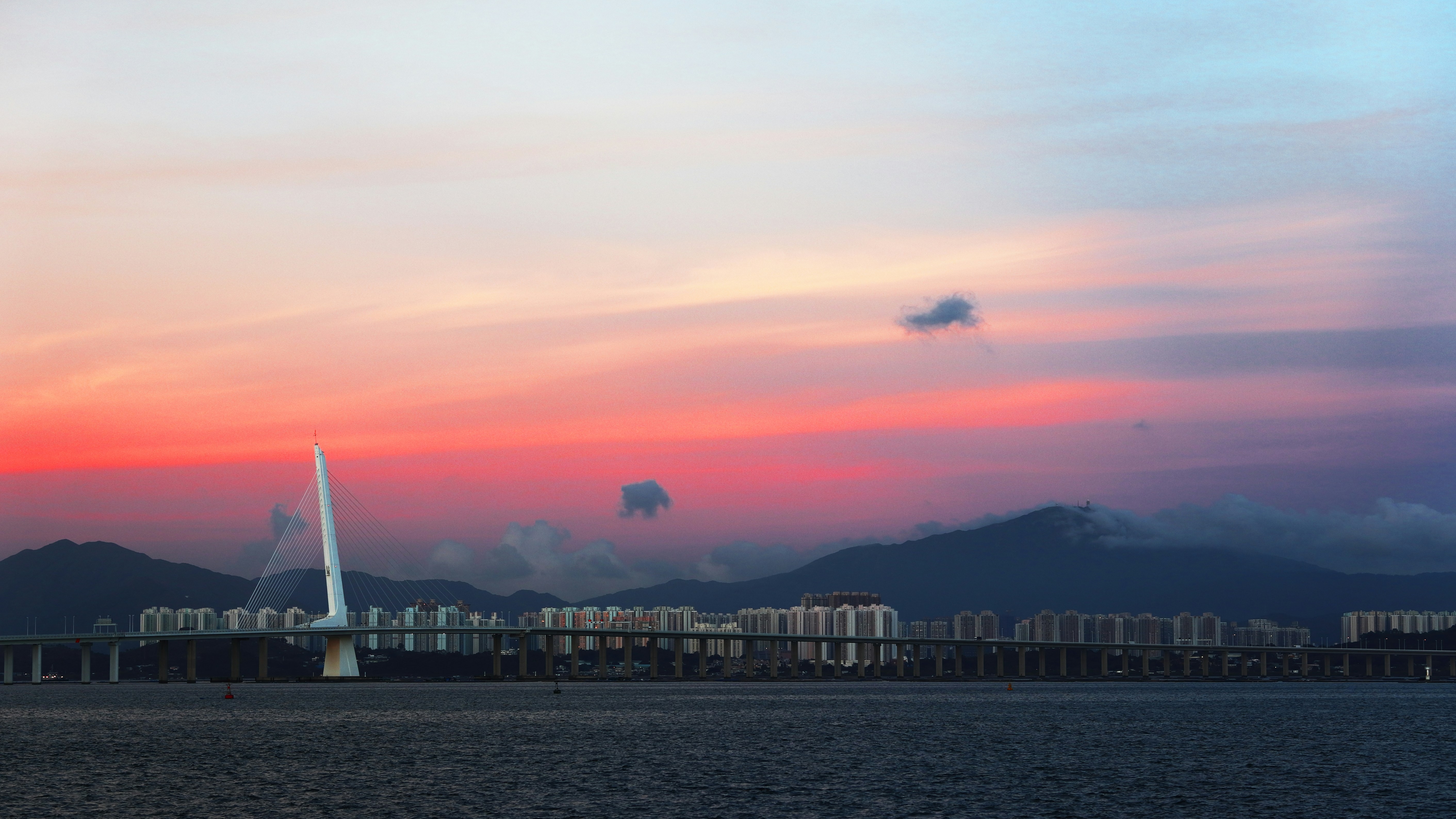 Crimson Dusk Drapes a Coastal Cable-Stayed Bridge Over a Quiet Inlet