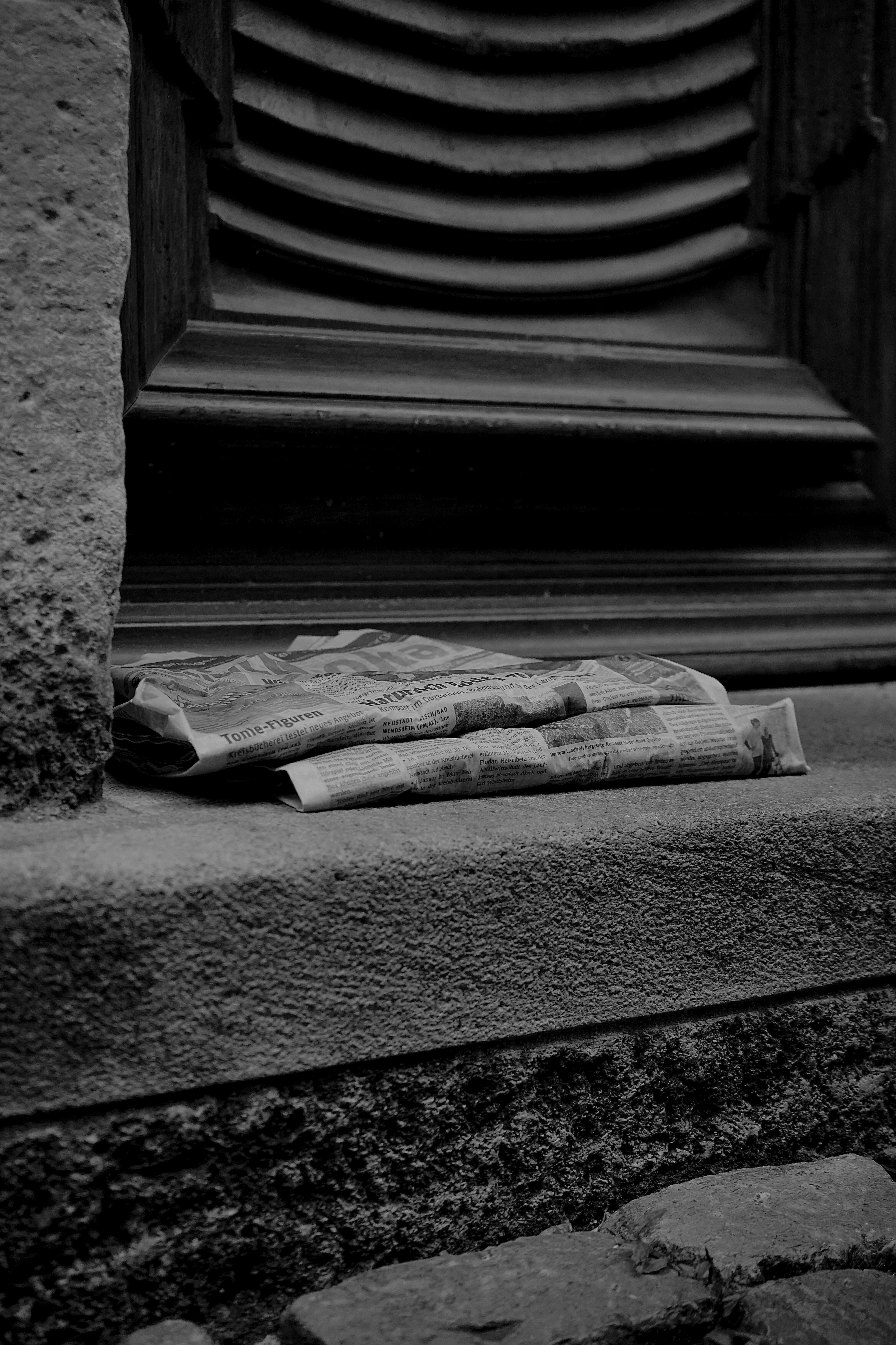 A newspaper laying on the ground in front of a window photo – Free Food ...