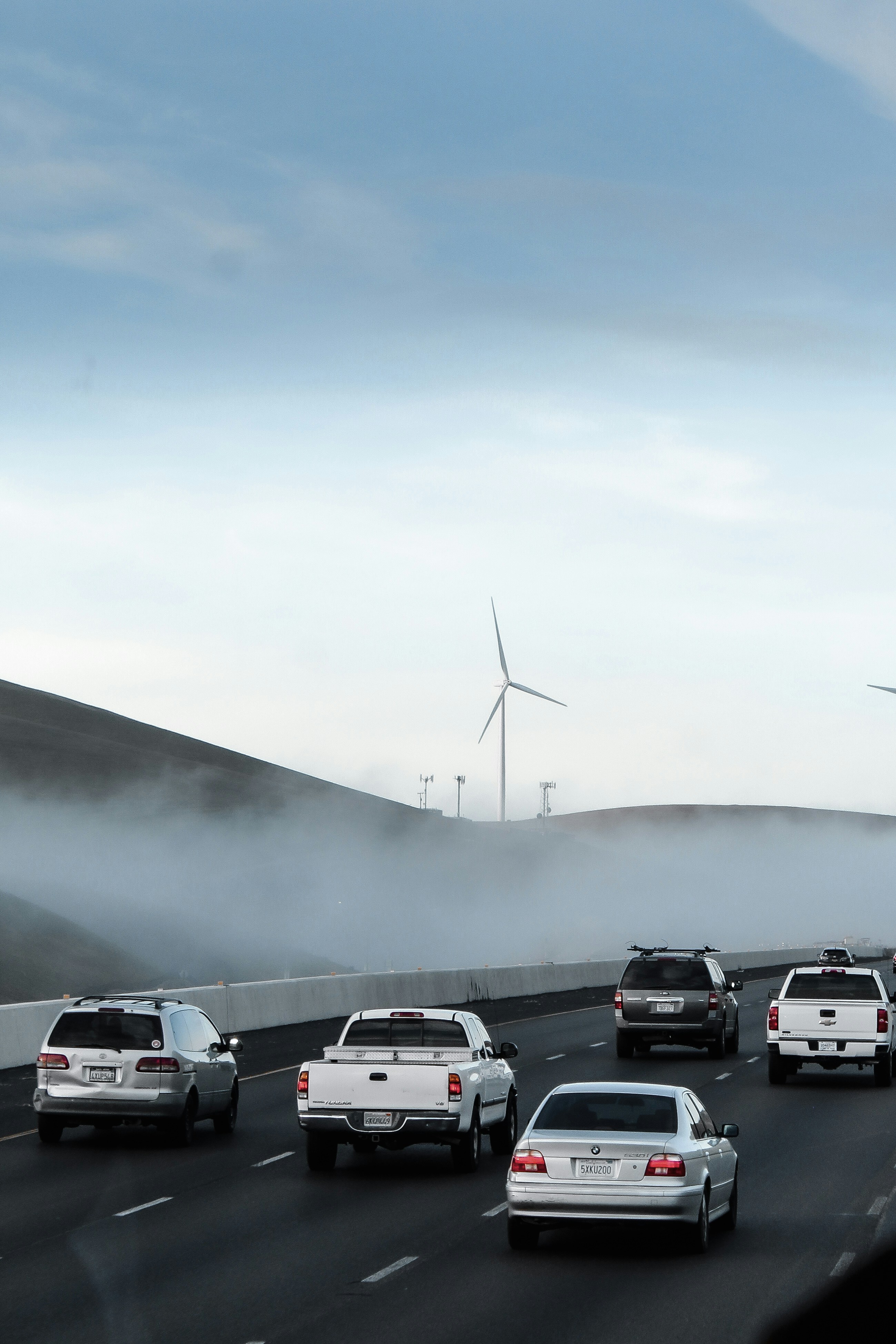 A group of cars driving down a highway next to wind turbines photo ...