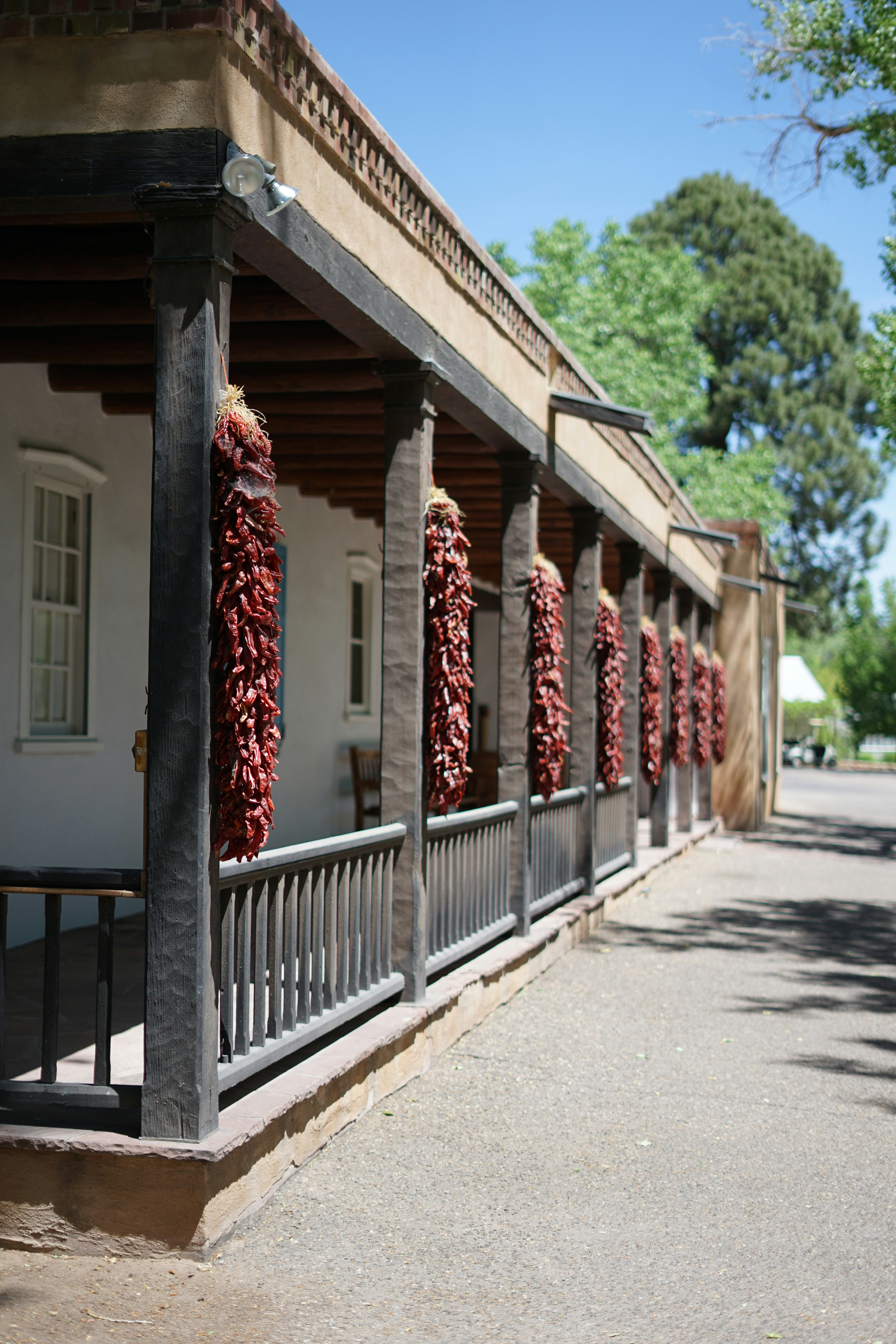Dried red chilies hanging from a rustic porch, highlighting traditional culinary practices in a historic setting.