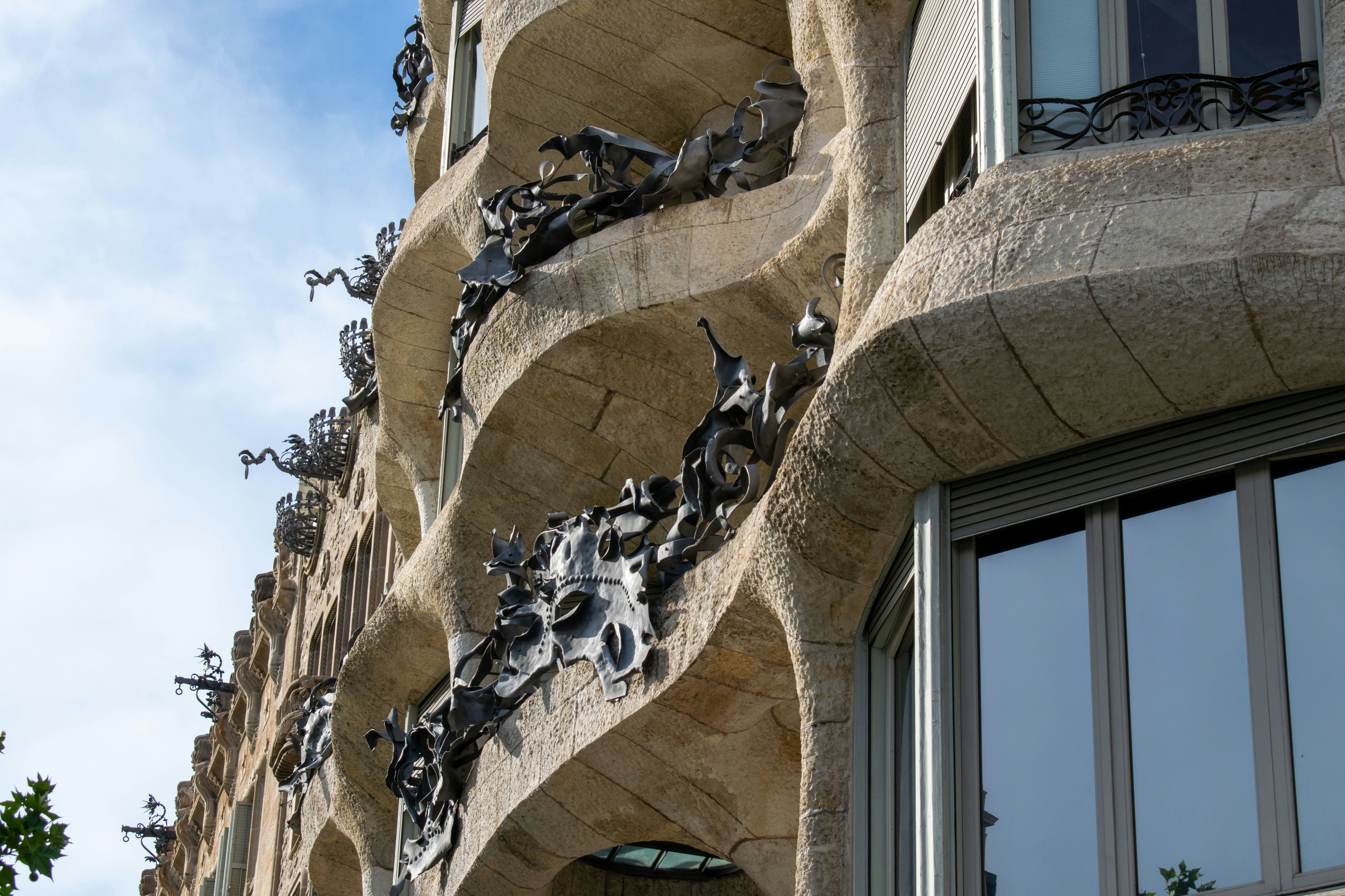 Intricate sculptures adorn the flowing façade of a modernist building, showcasing a blend of organic shapes and artistic craftsmanship.