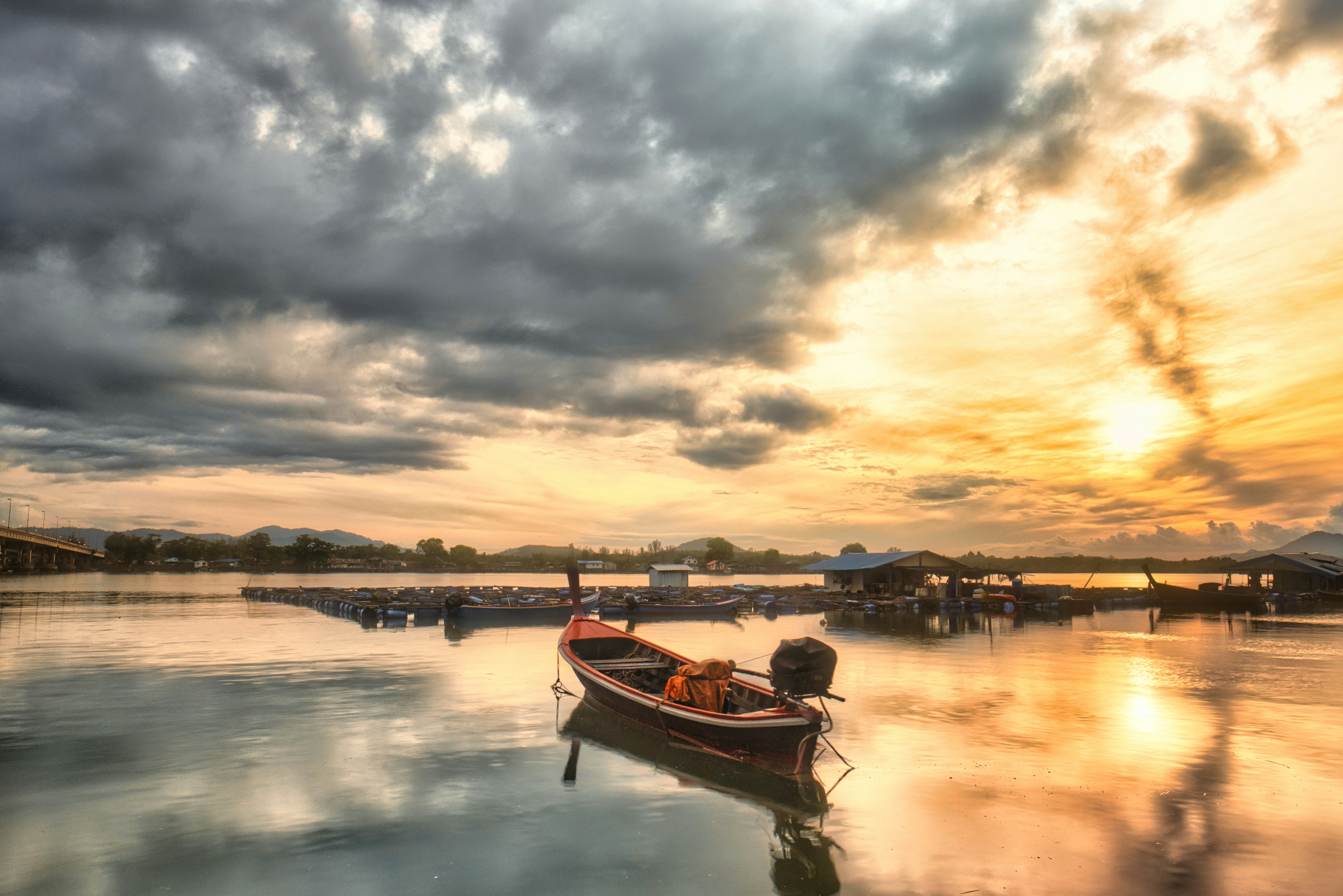 a boat floating on top of a lake under a cloudy sky