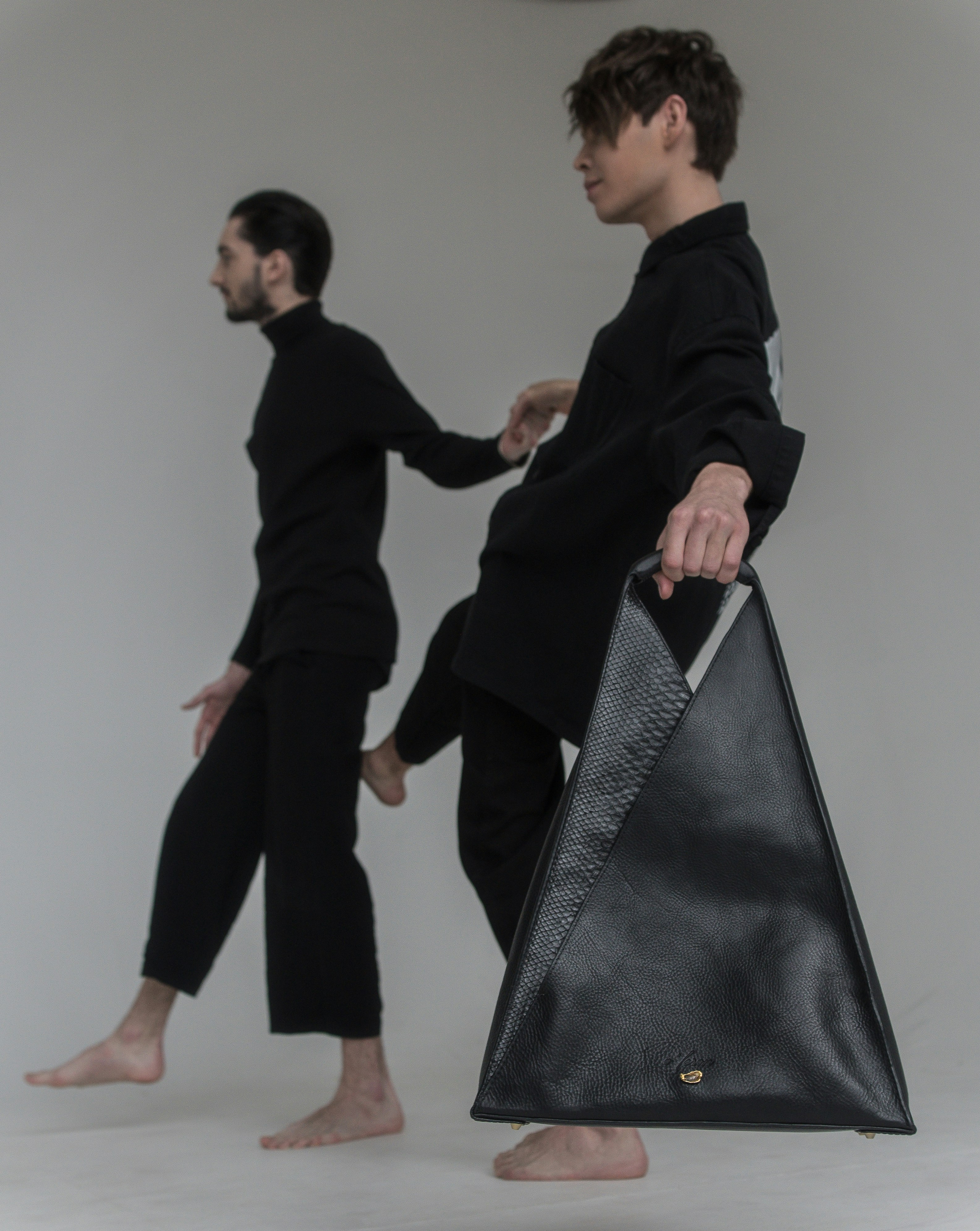 Monochrome Motion: A Triangular Leather Prop in a Studio Duet