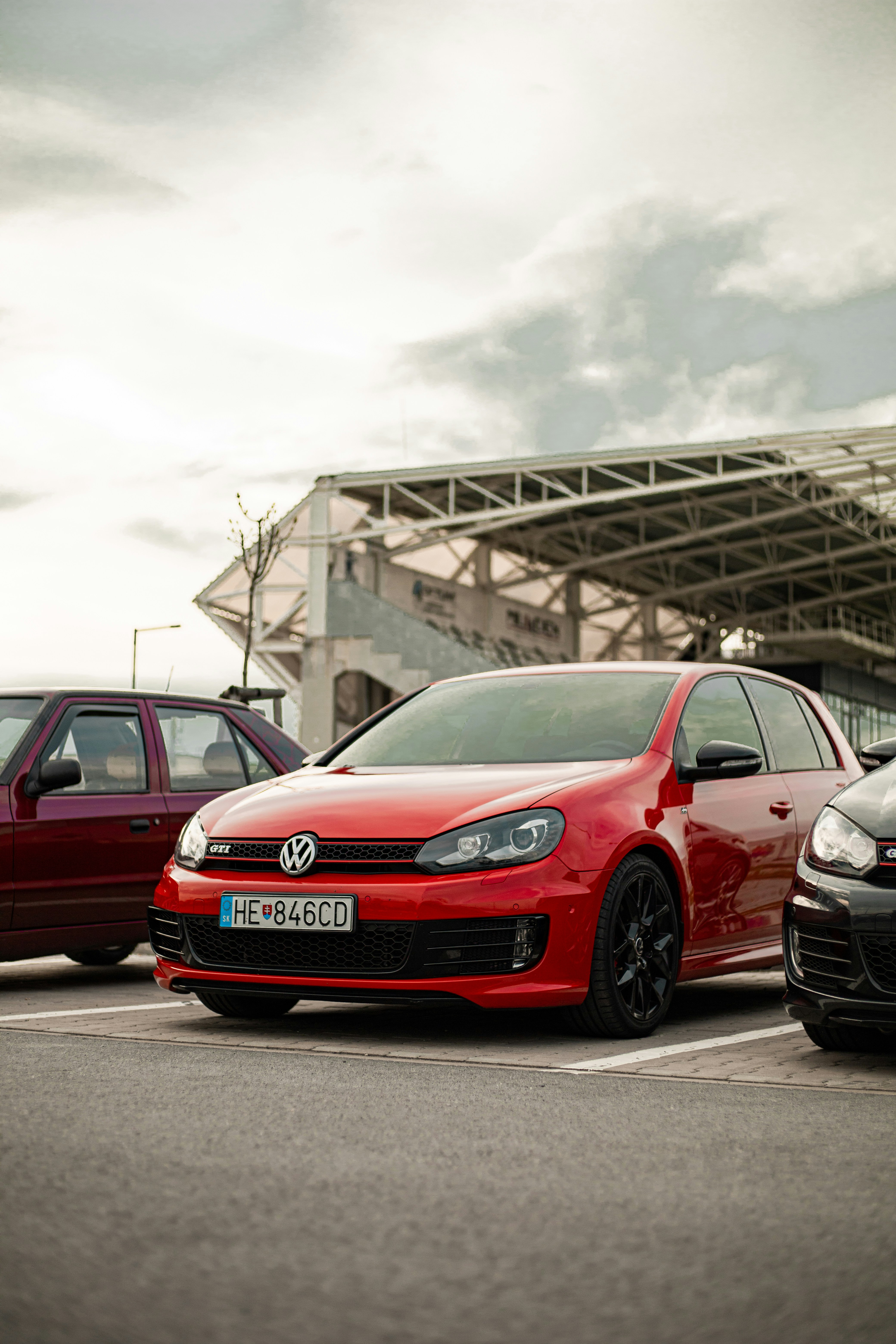 Red Volkswagen GTI in a Parking Lot Under a Partially Cloudy Sky