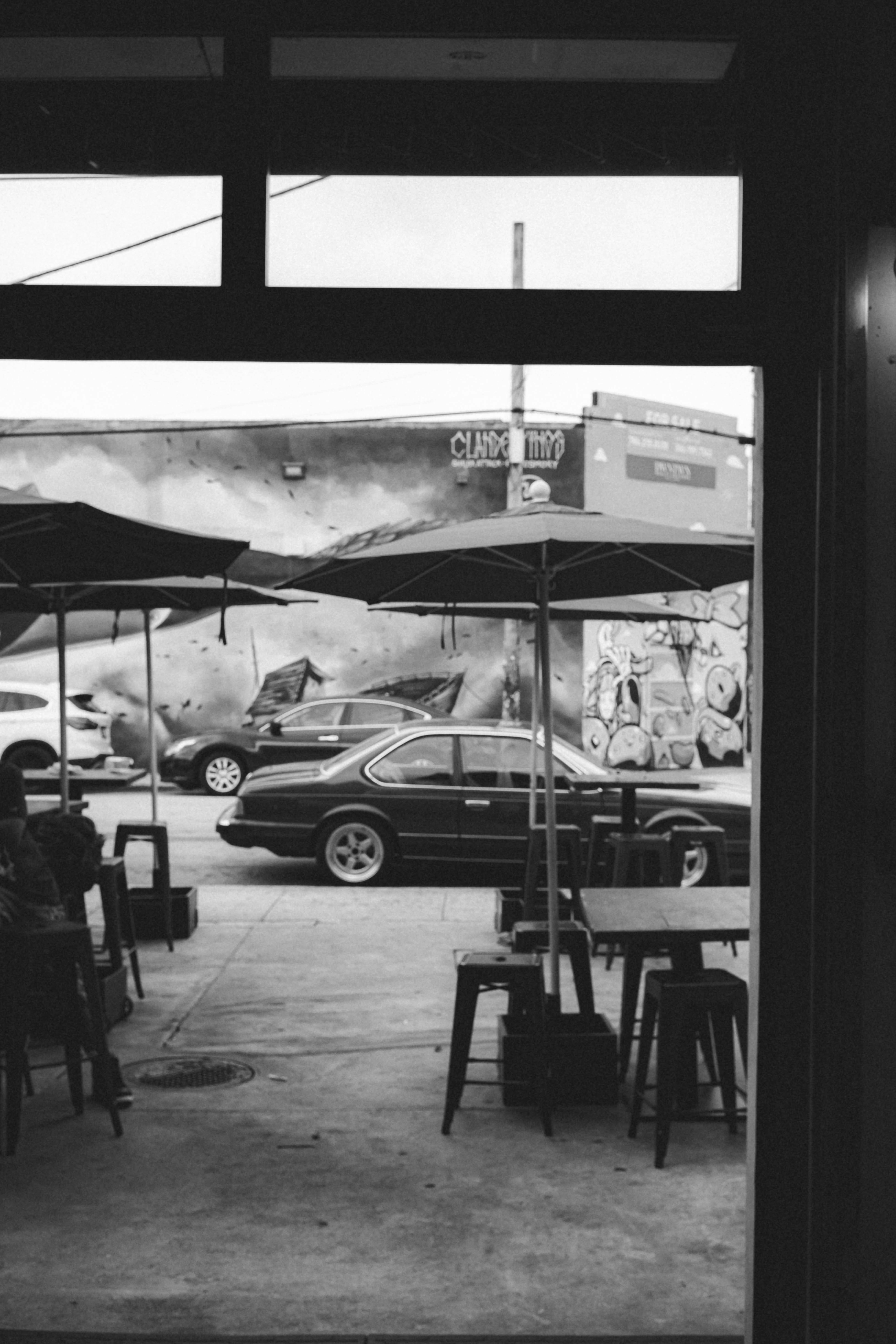 Streetside Quiet: Car, Mural, and Market Table in Monochrome
